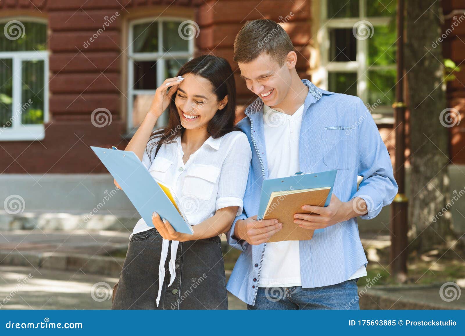 Cheerful Couple of University Friends Laughing Outdoors while Checking ...