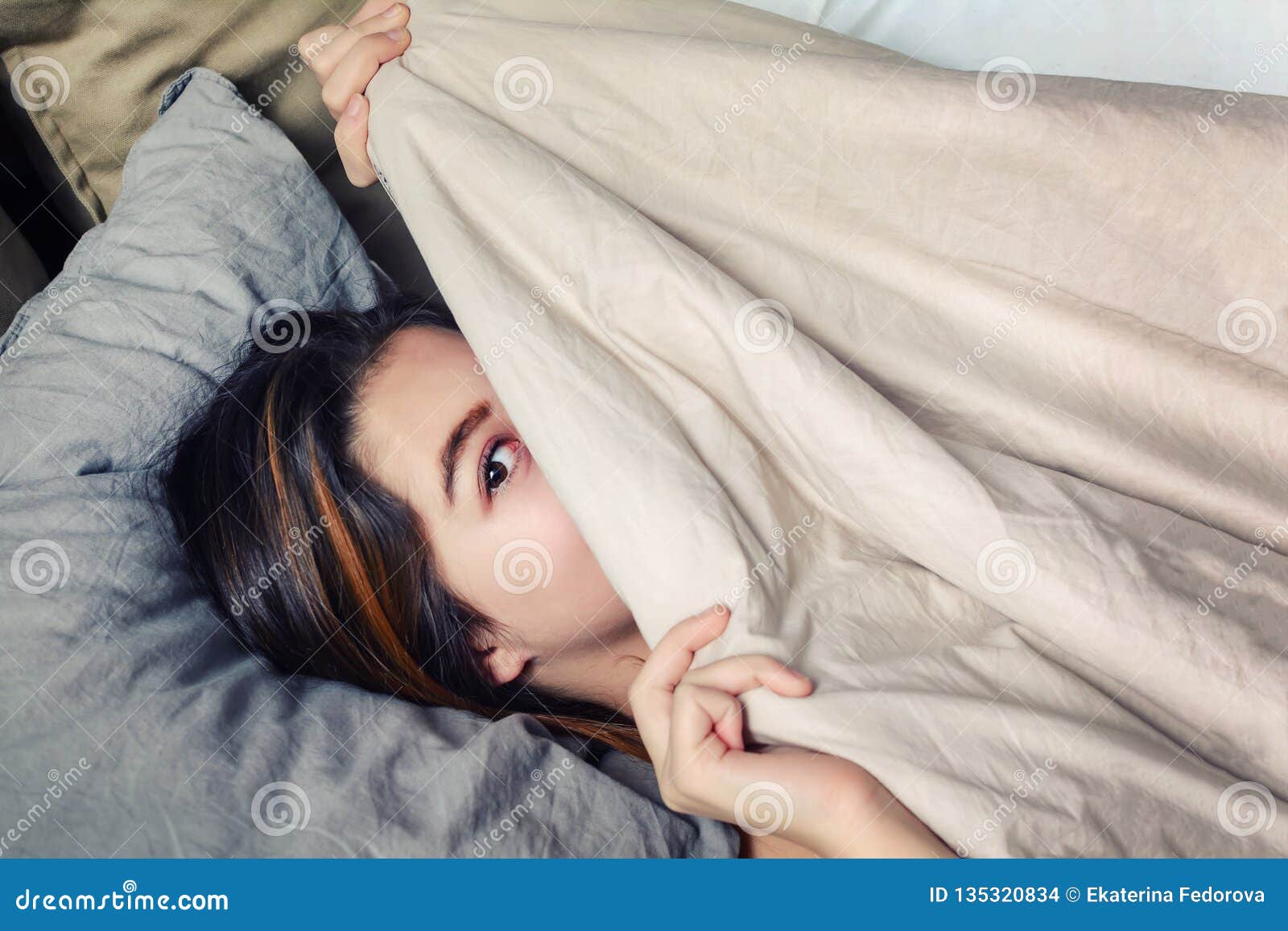 Cheerful Girl With Dark Hair Hides Her Face Under A Blanket Portrait