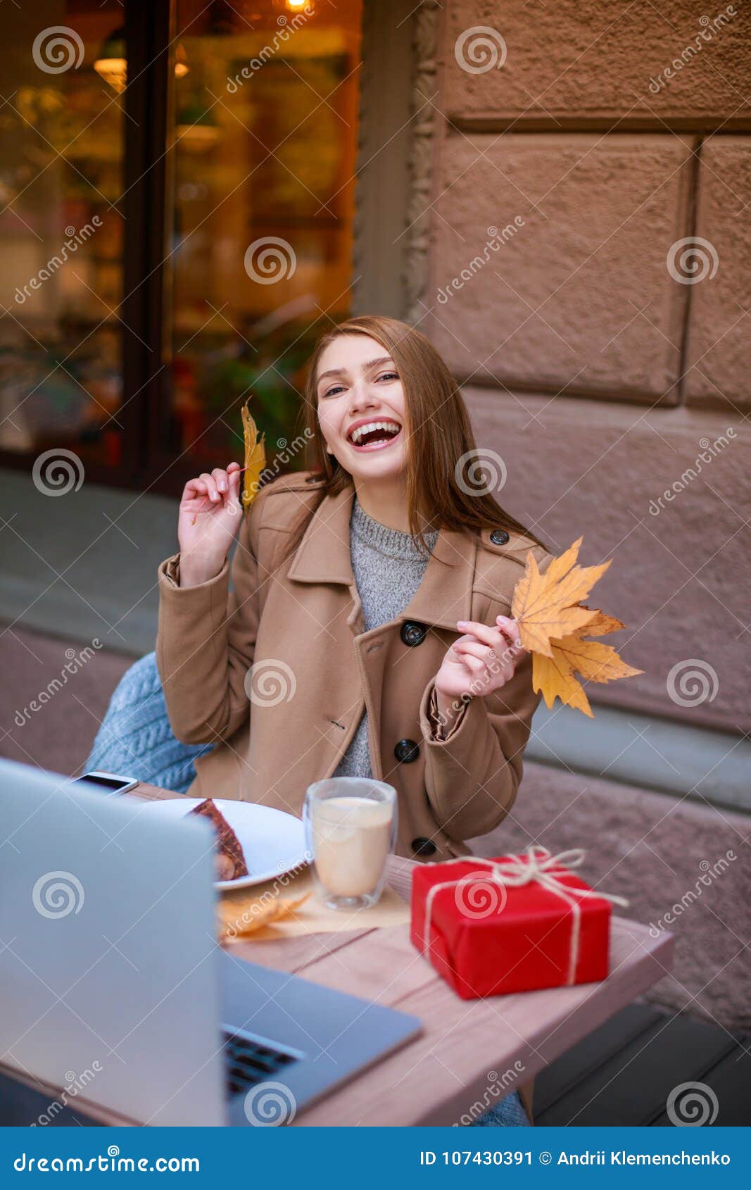 A Cheerful Girl Sits In A Cafe Holds Two Autumn Leaves And Laughs Happily Stock Image Image