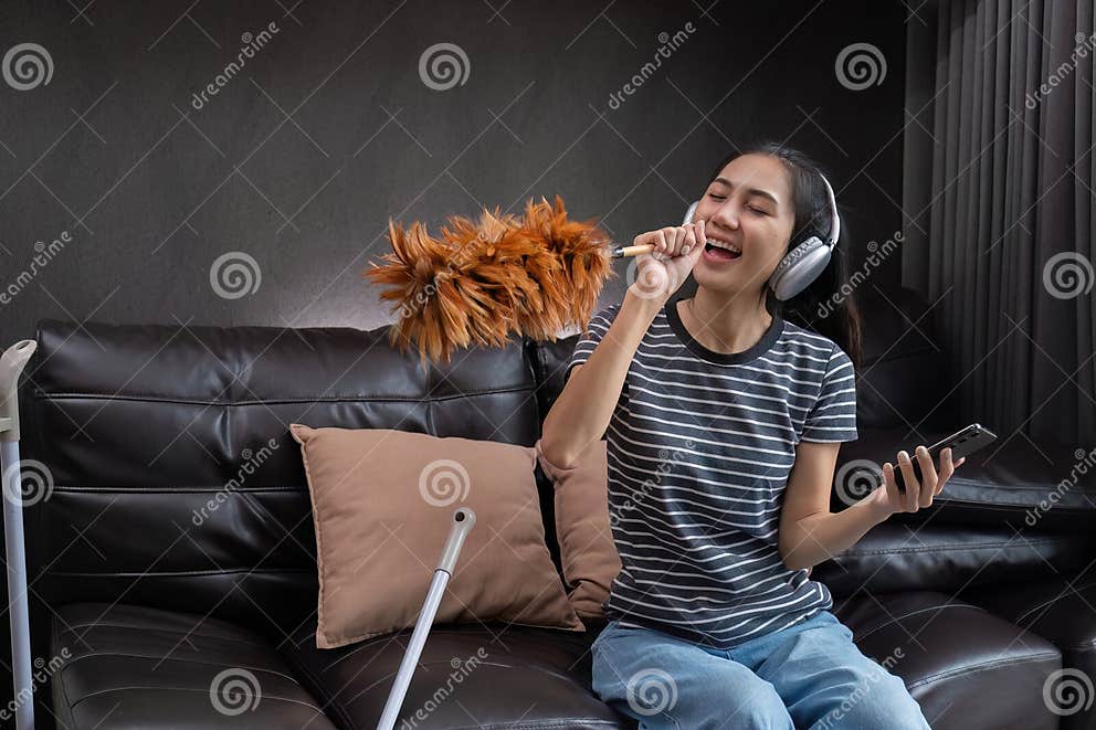 Cheerful And Happy Young Woman Singing And Dancing While Cleaning The