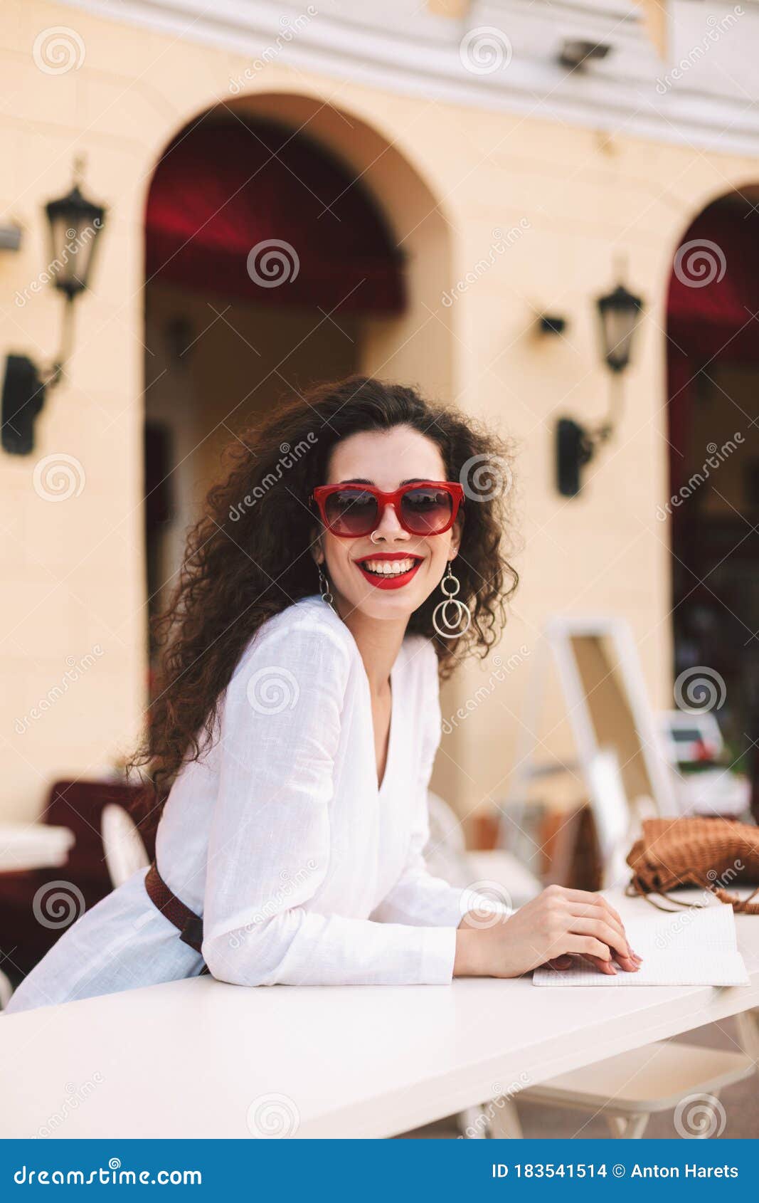 Cheerful Lady With Dark Curly Hair In Sunglasses Standing And Joyfully