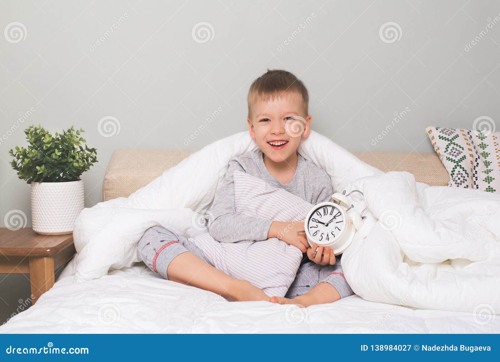 Cheerful Little Boy In Bed With Alarm Clock, Wake Up Morning Concept ... Cheerful Little Boy In Bed With Alarm Clock, Wake Up Morning Concept ...