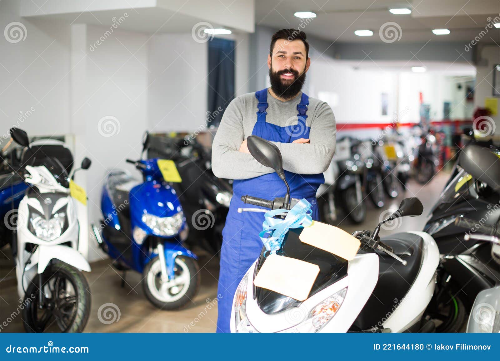 Cheerful Man Worker Displaying Various Motorcycles in Workshop Stock ...