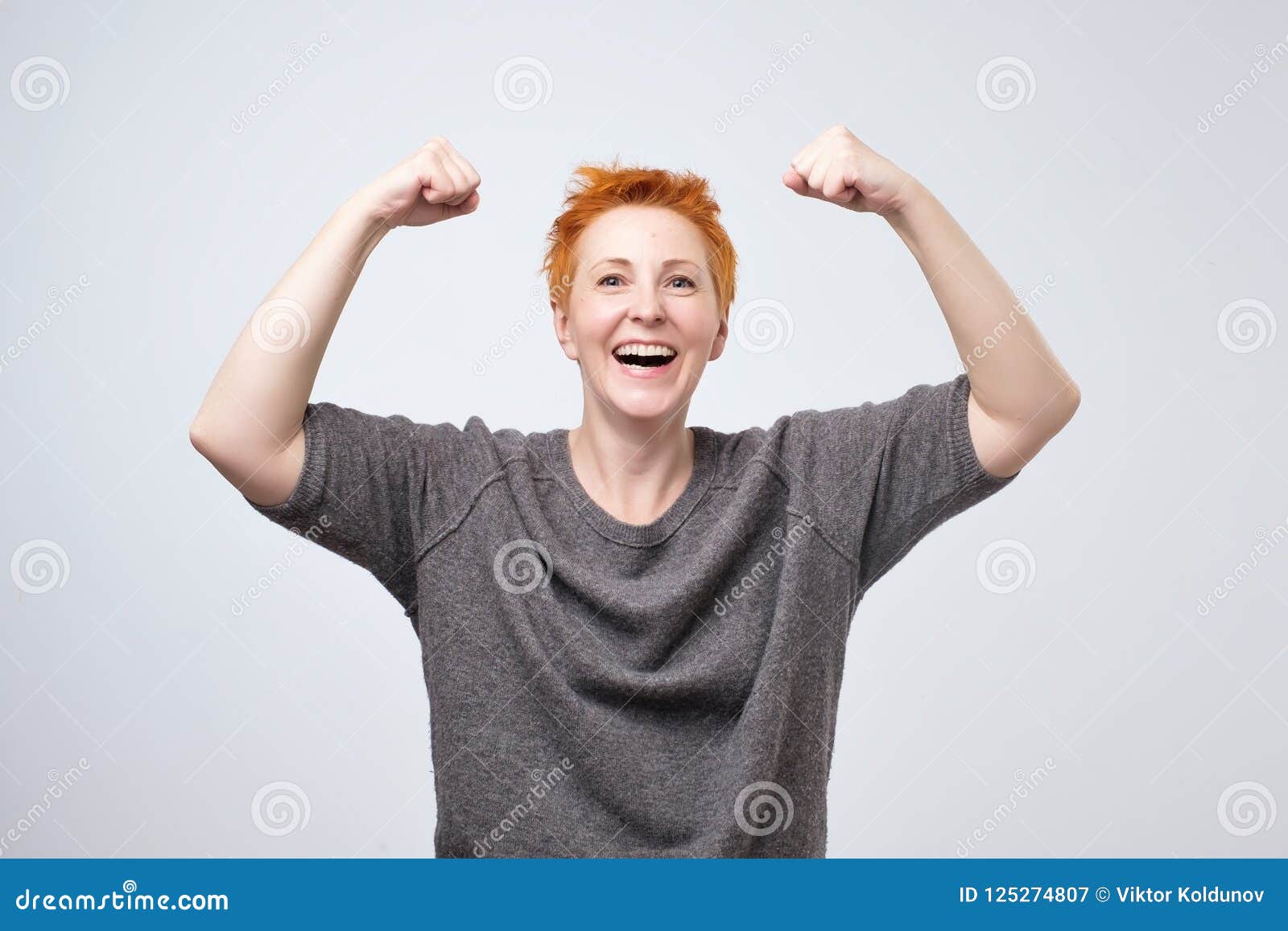 Cheerful Mature Woman Smiling With Raised Fists Showing Her Strength
