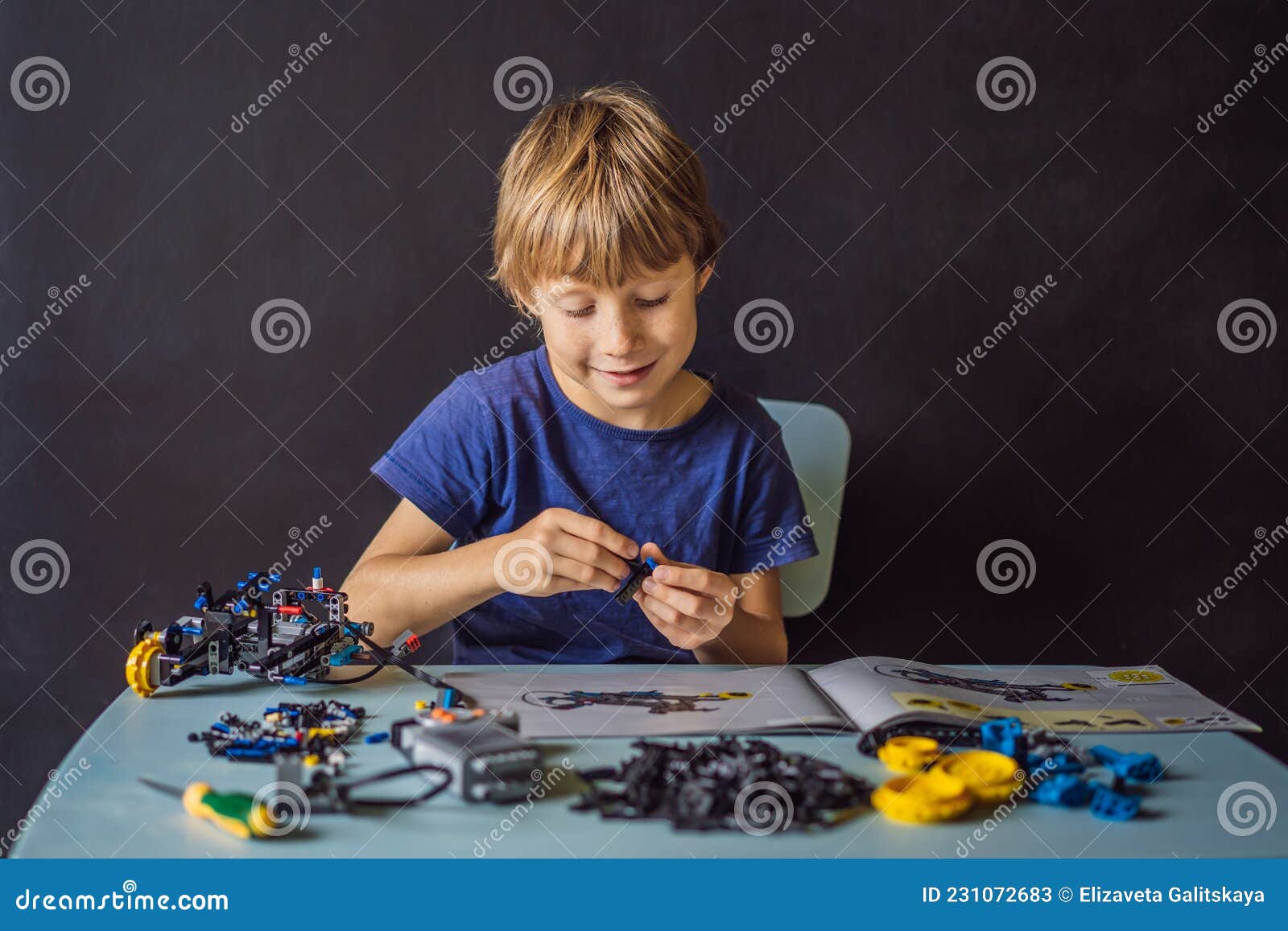 Cheerful Smart Schoolboy Sitting at the Table and Constructing a ...