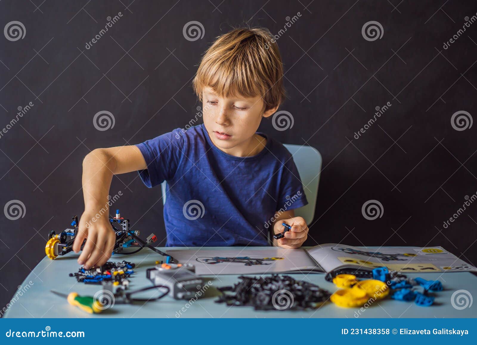 Cheerful Smart Schoolboy Sitting at the Table and Constructing a ...