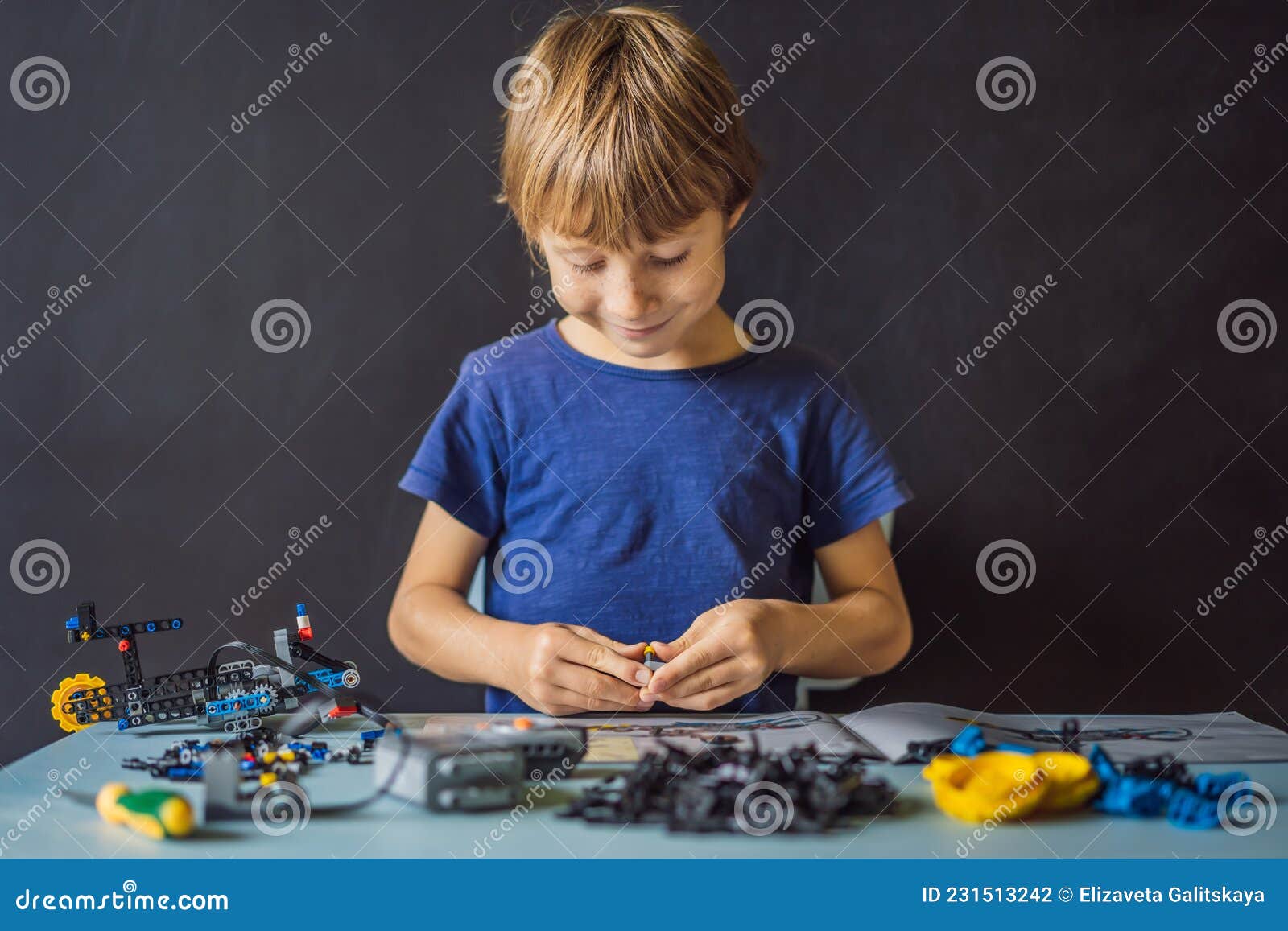 Cheerful Smart Schoolboy Sitting at the Table and Constructing a ...