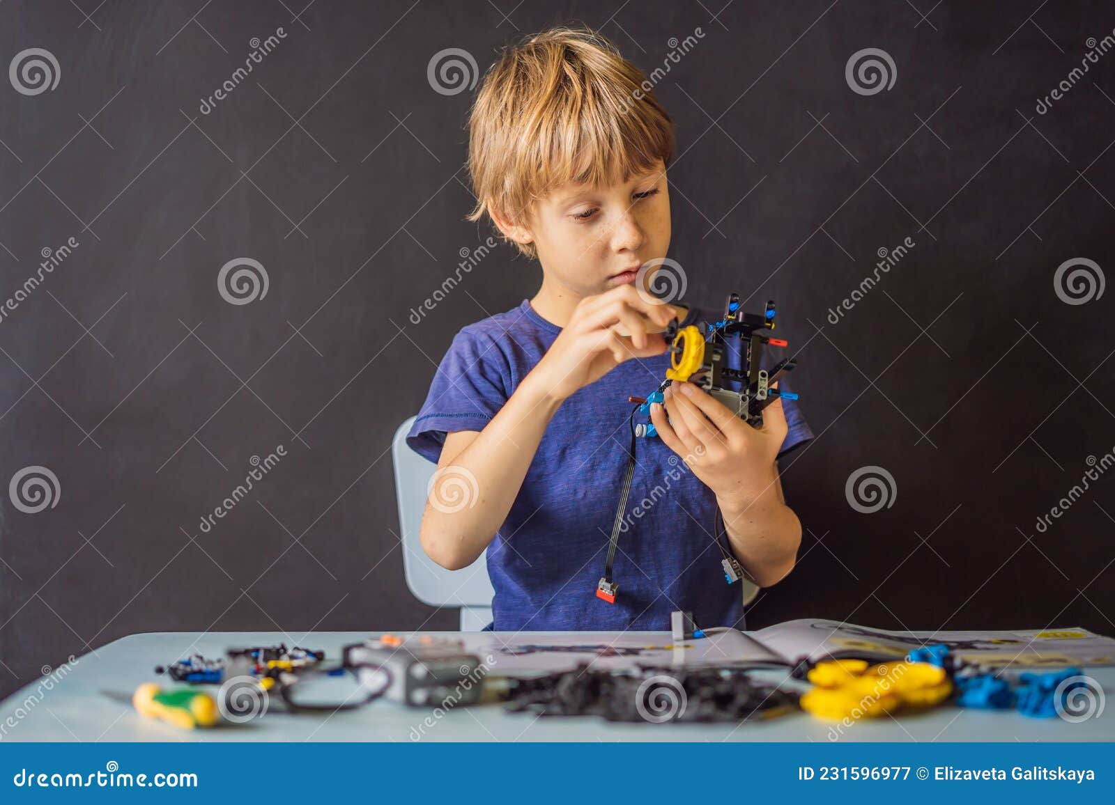 Cheerful Smart Schoolboy Sitting at the Table and Constructing a ...
