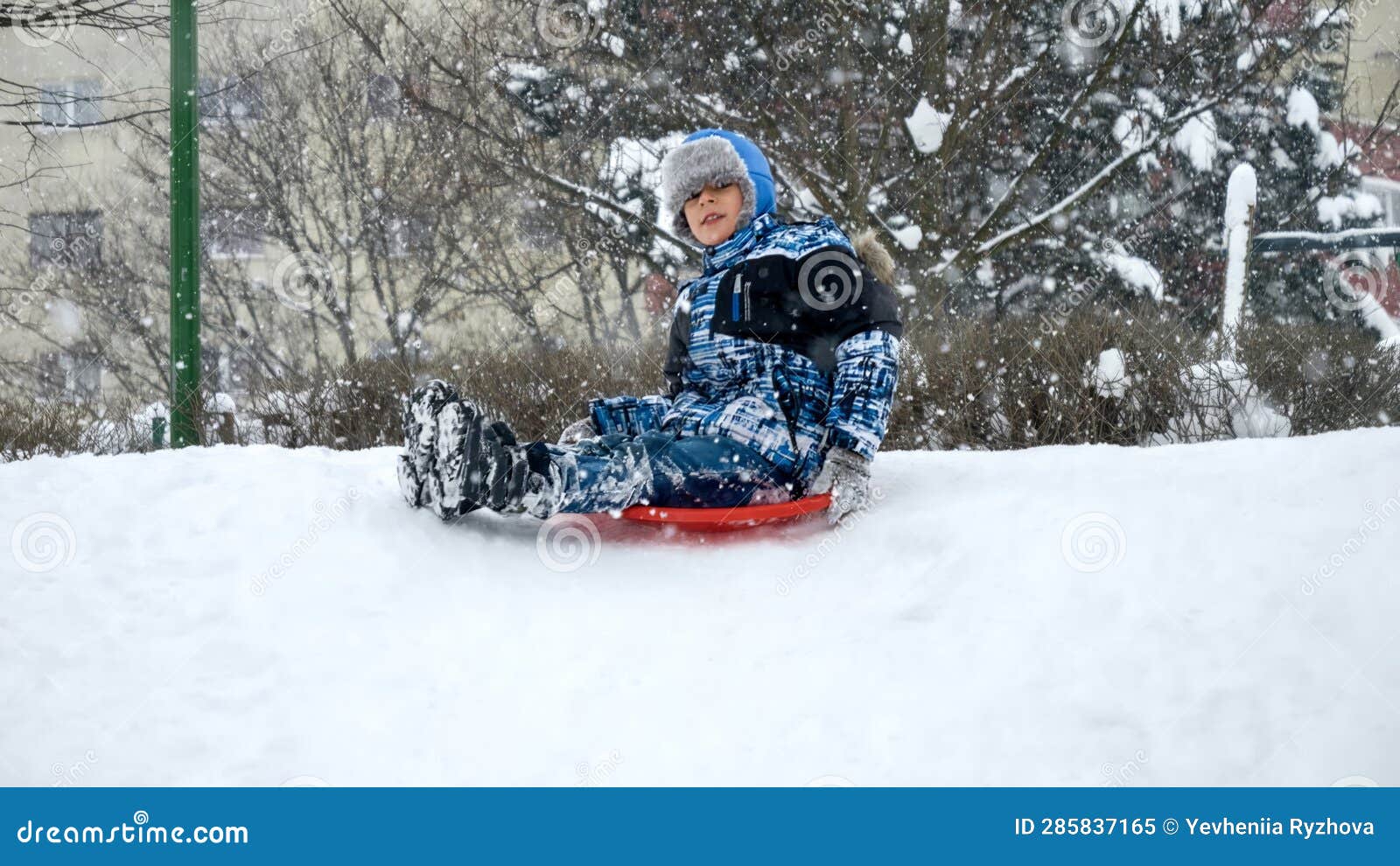 Cheerful Smiling Boy Riding Down the Snowy Hill on Red Plastic Sleds ...