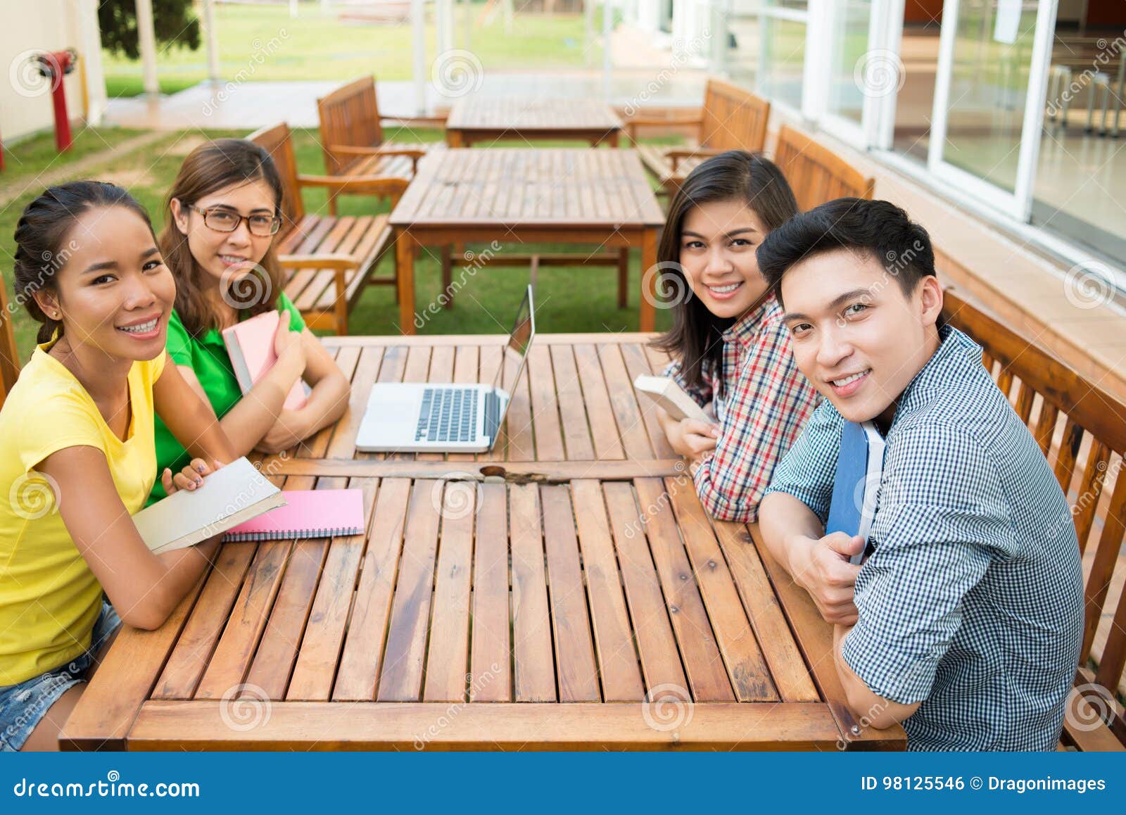Cheerful students at table stock photo. Image of friends - 98125546