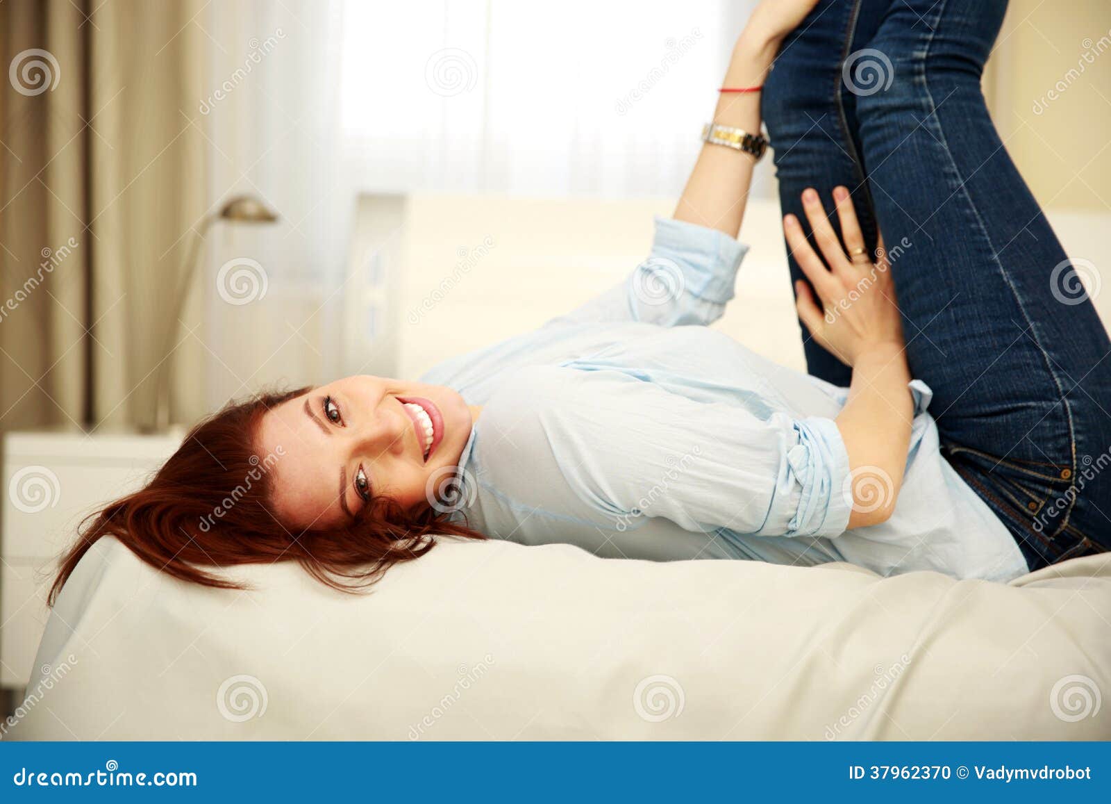 Cheerful Woman Lying on the Bed with Raised Legs Stock Photo - Image of ...