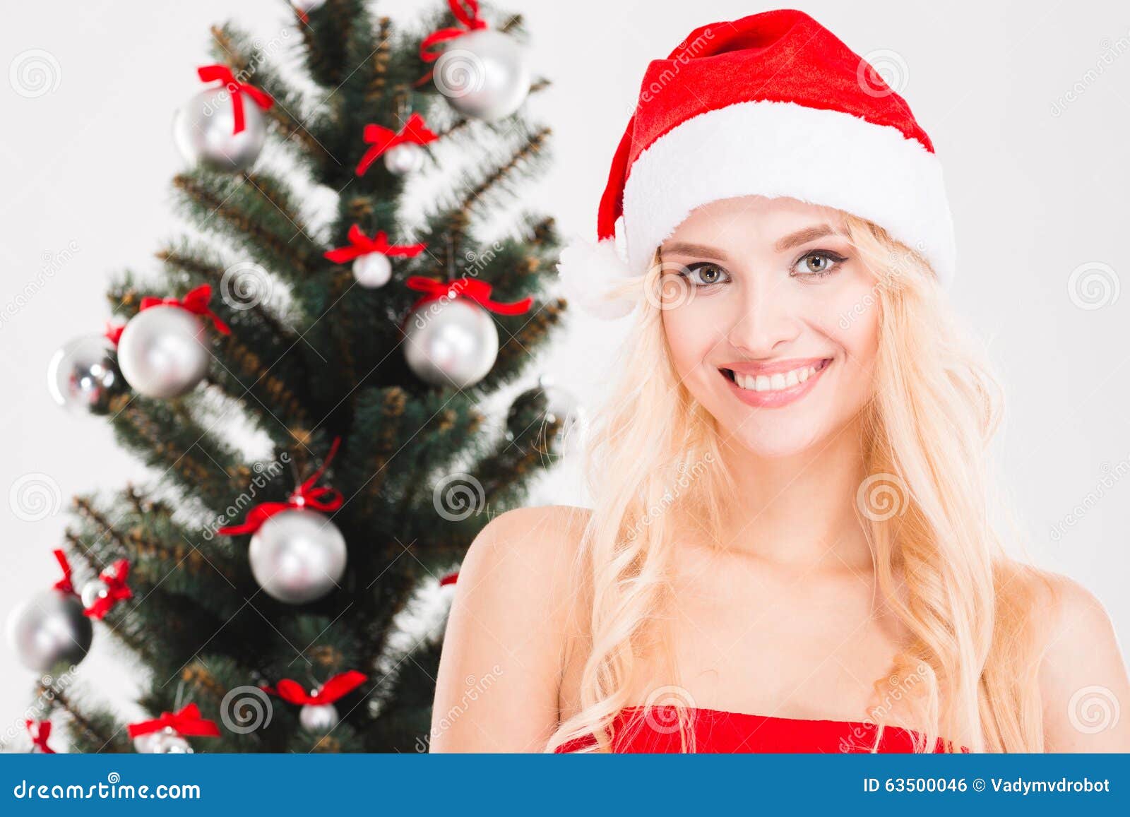 Cheerful Woman In Santa Claus Hat Posing Near Christmas Tree Stock