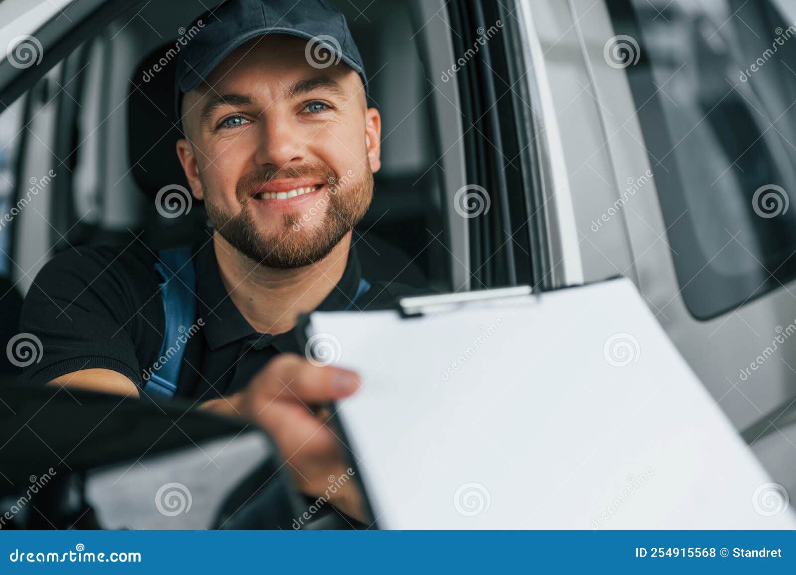Cheerful Worker. Delivery Man in Uniform is Indoors with Car and with ...