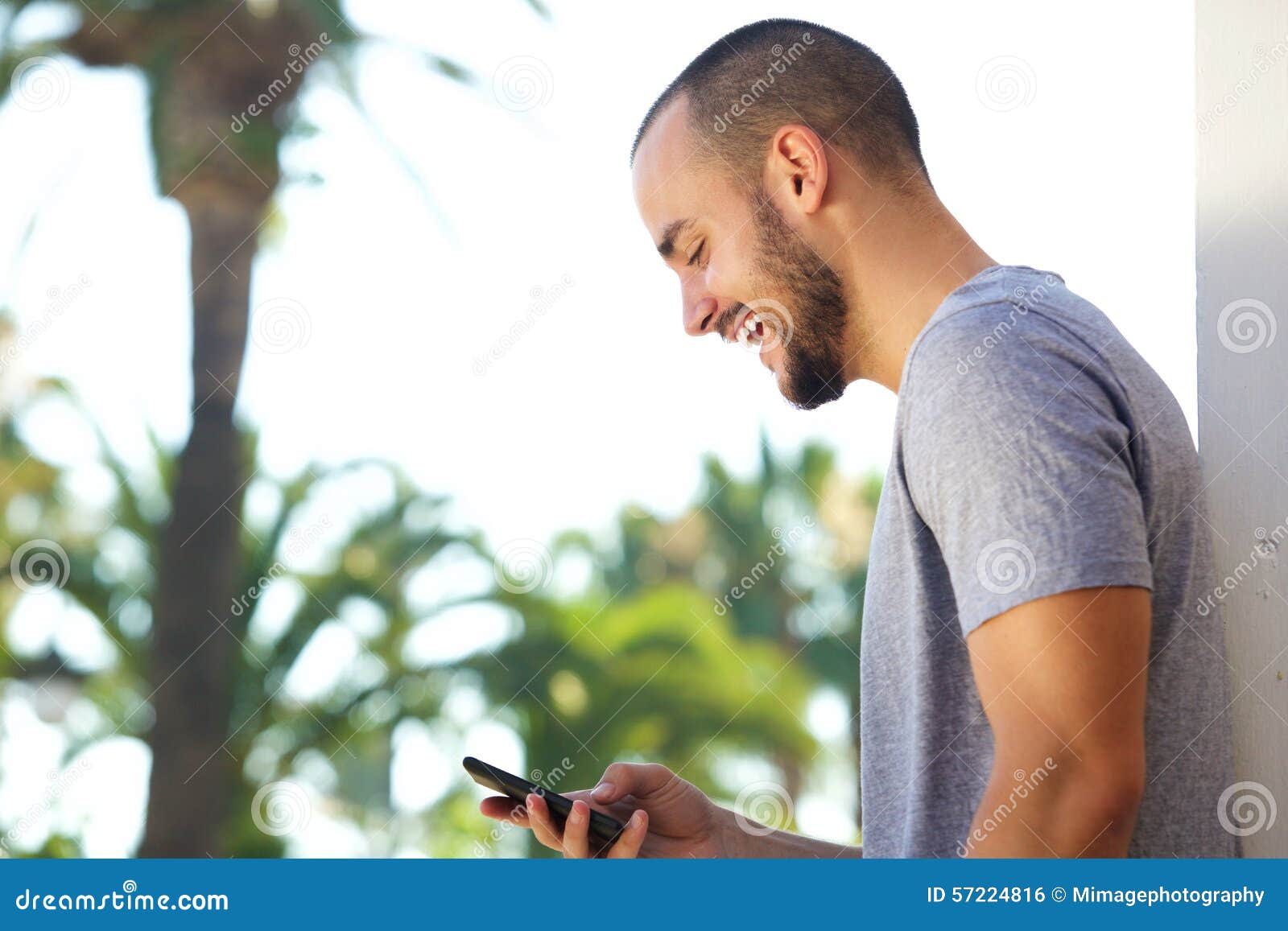Cheerful Young Man Reading Text Message on Mobile Phone Stock Photo ...