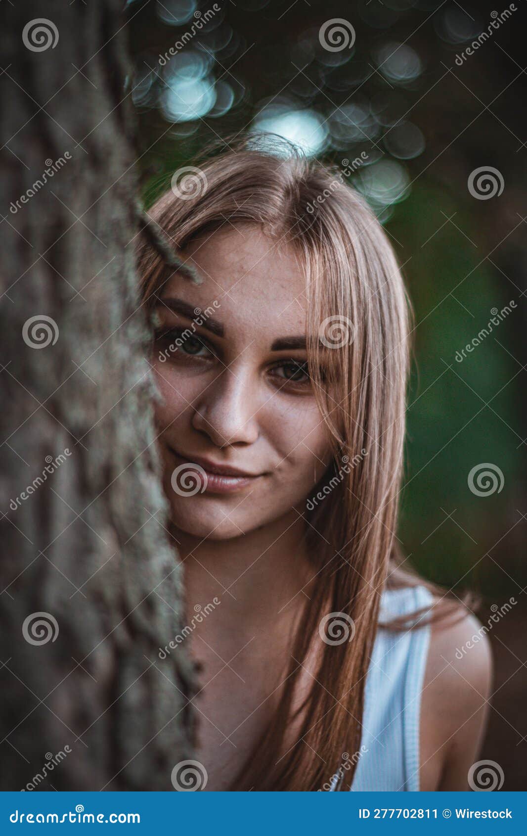 A Young Woman Smiles while Leaning on a Tree Trunk in the Forest Stock ...