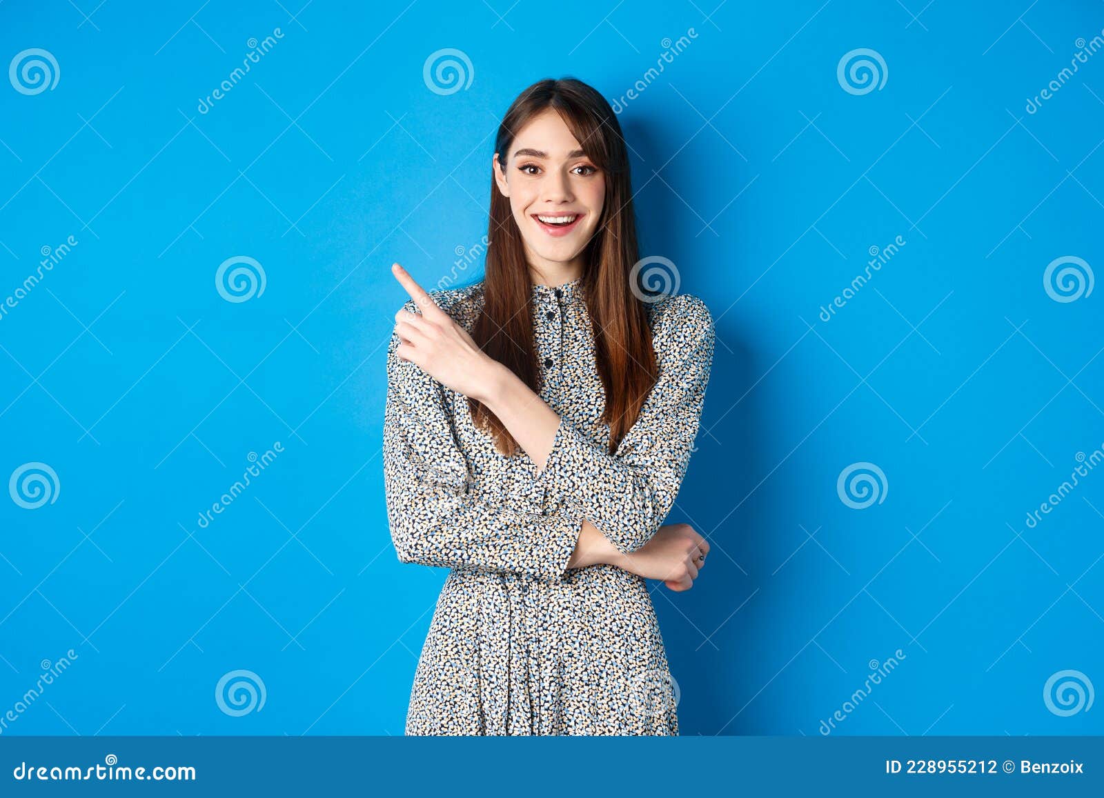 Cheerful Young Woman In Long Dress Smiling Pointing Finger At Upper