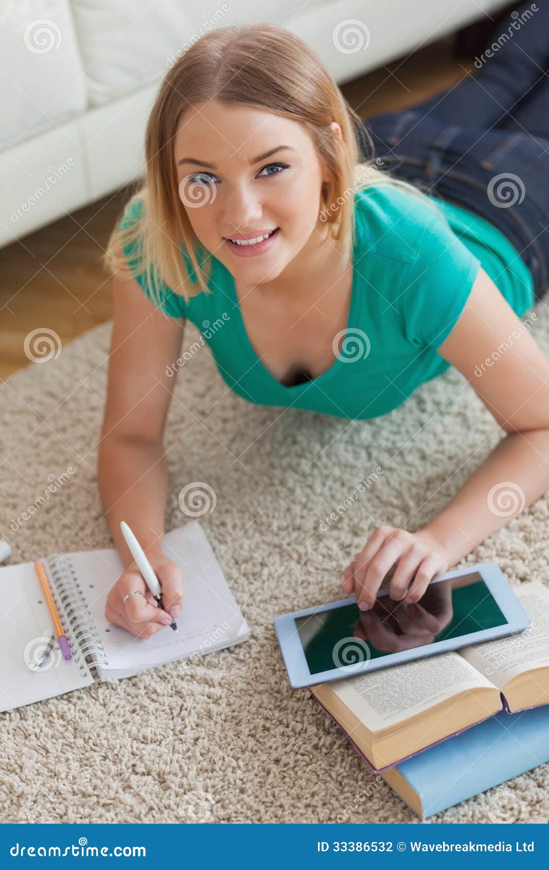 Cheerful Young Woman Lying on Floor Using Tablet To Do Her Assignment ...