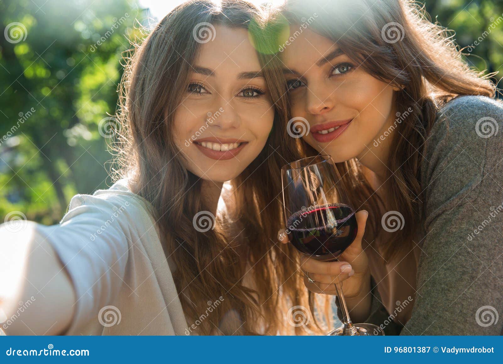 Cheerful Young Women Outdoors In Park Drinking Wine Make Selfie Stock