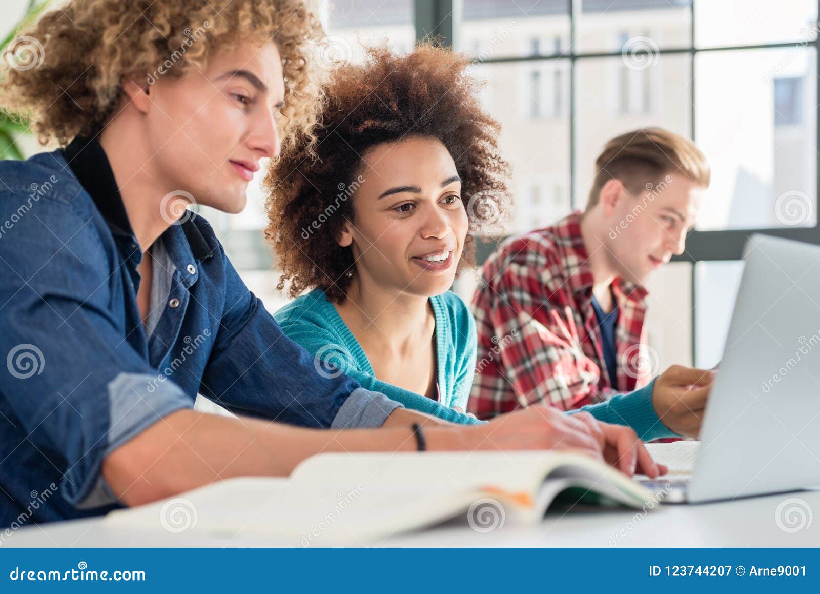 Cheerful Woman Writing an Assignment while Sitting between Two ...
