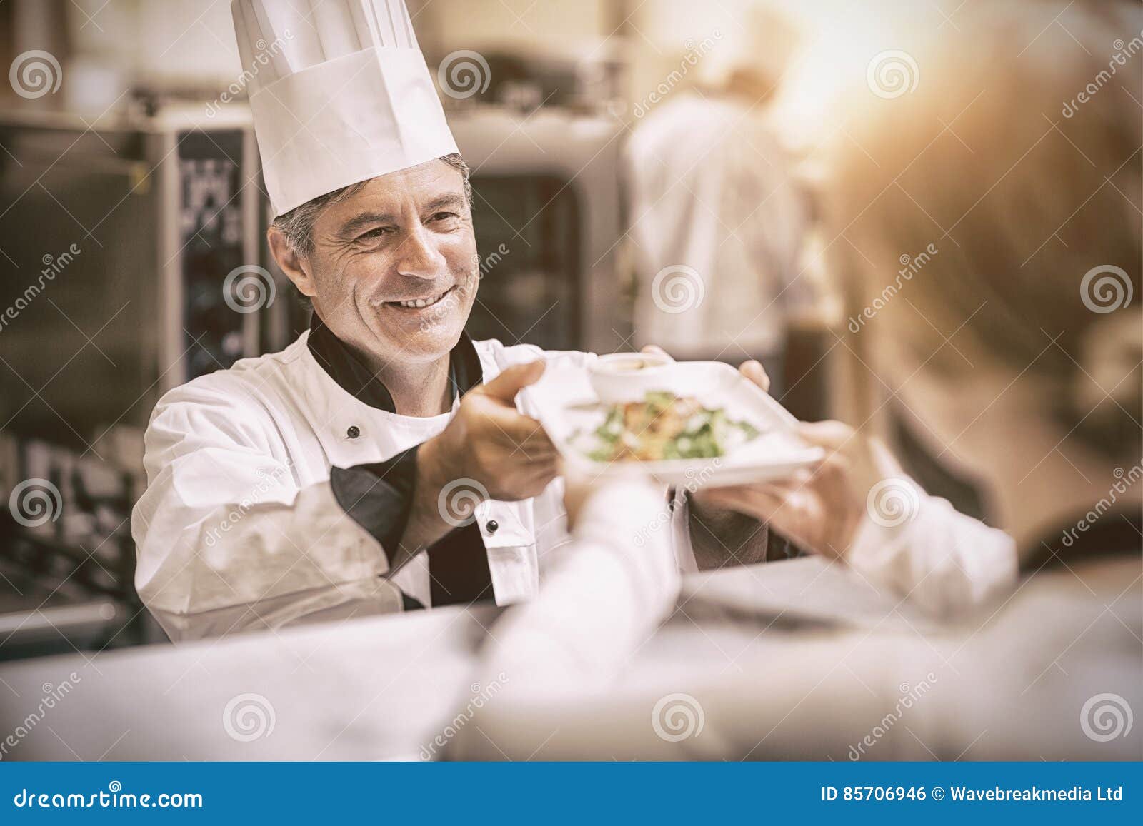 Chef Handing Dinner Dish To Waitress at Order Station Stock Photo ...