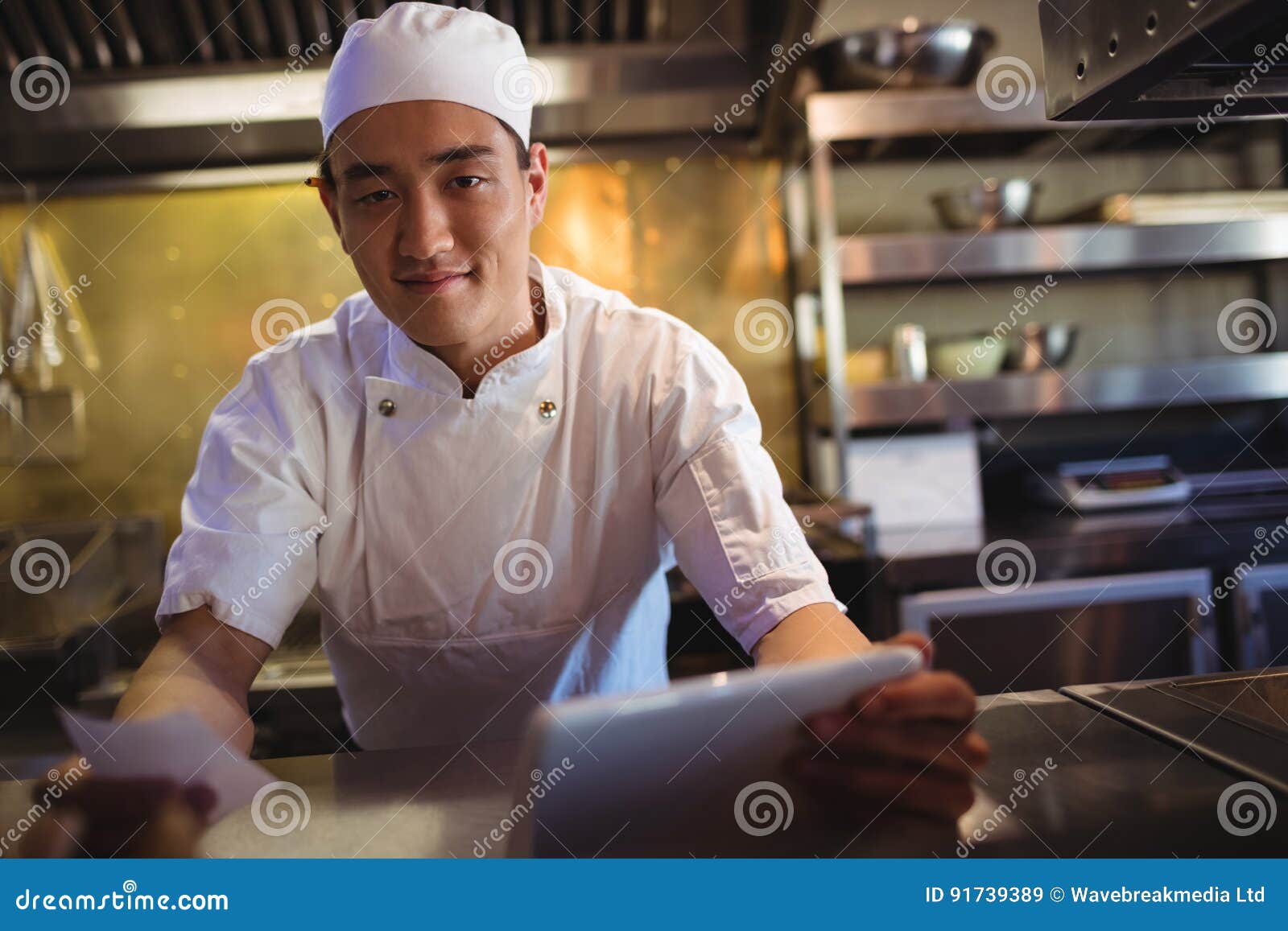 Chef Holding Digital Tablet and an Order List in the Commercial Kitchen ...