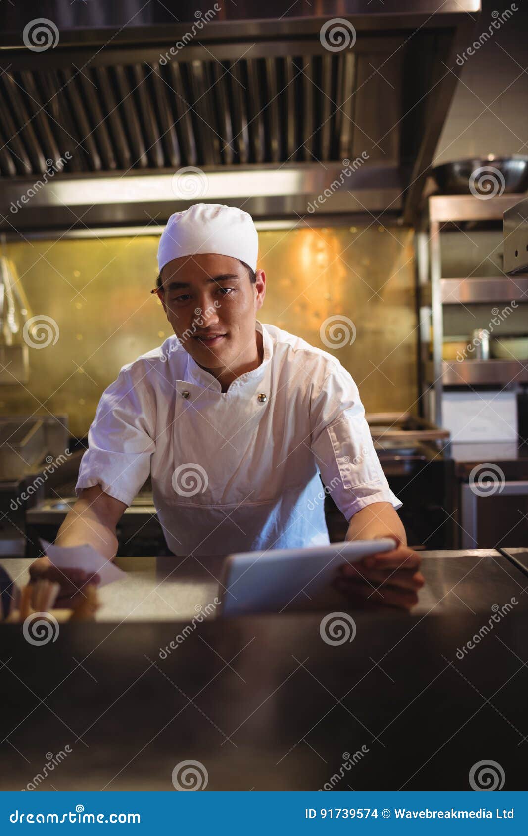 Chef Holding Digital Tablet and an Order List in the Commercial Kitchen ...