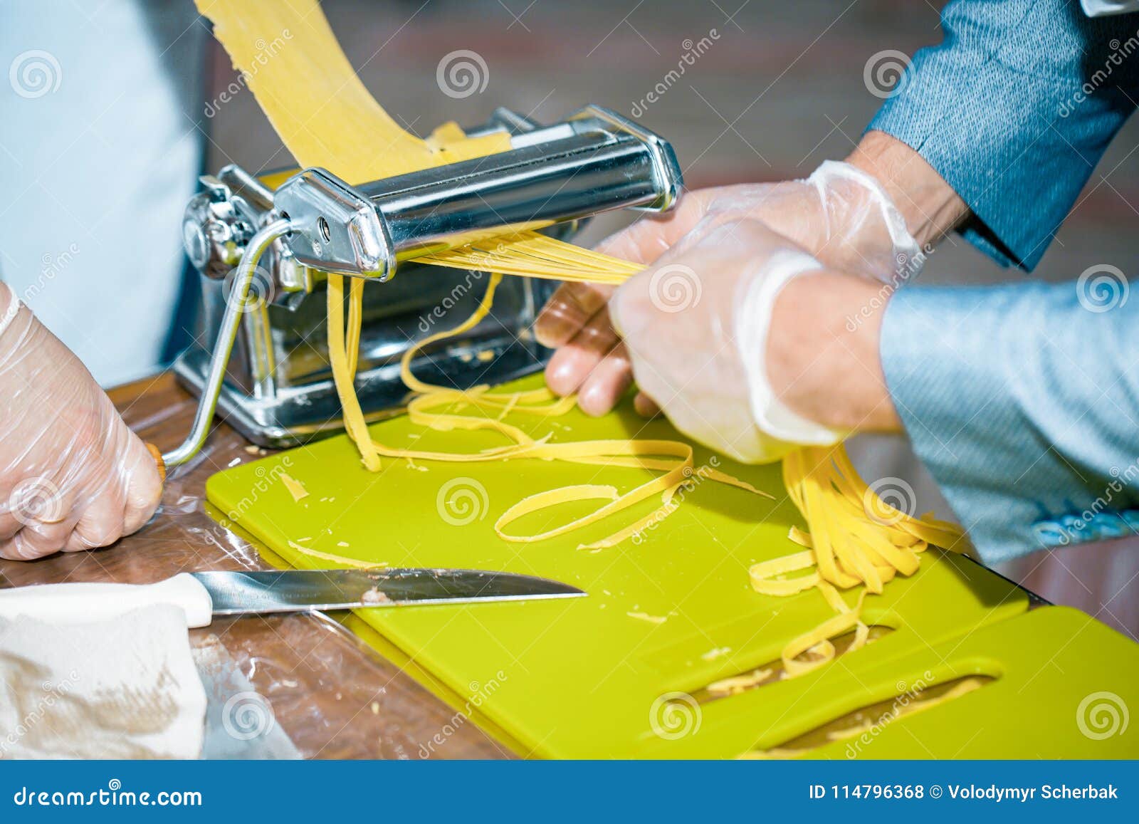 Chef Making Spaghetti Noodles with Pasta Machine on Kitchen Table Stock ...