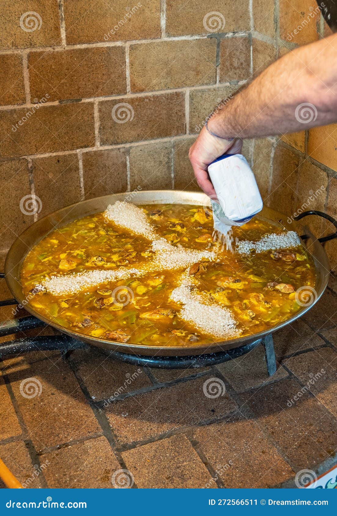 Chef Pouring Rice into the Paella after Cooking the First Ingredients ...