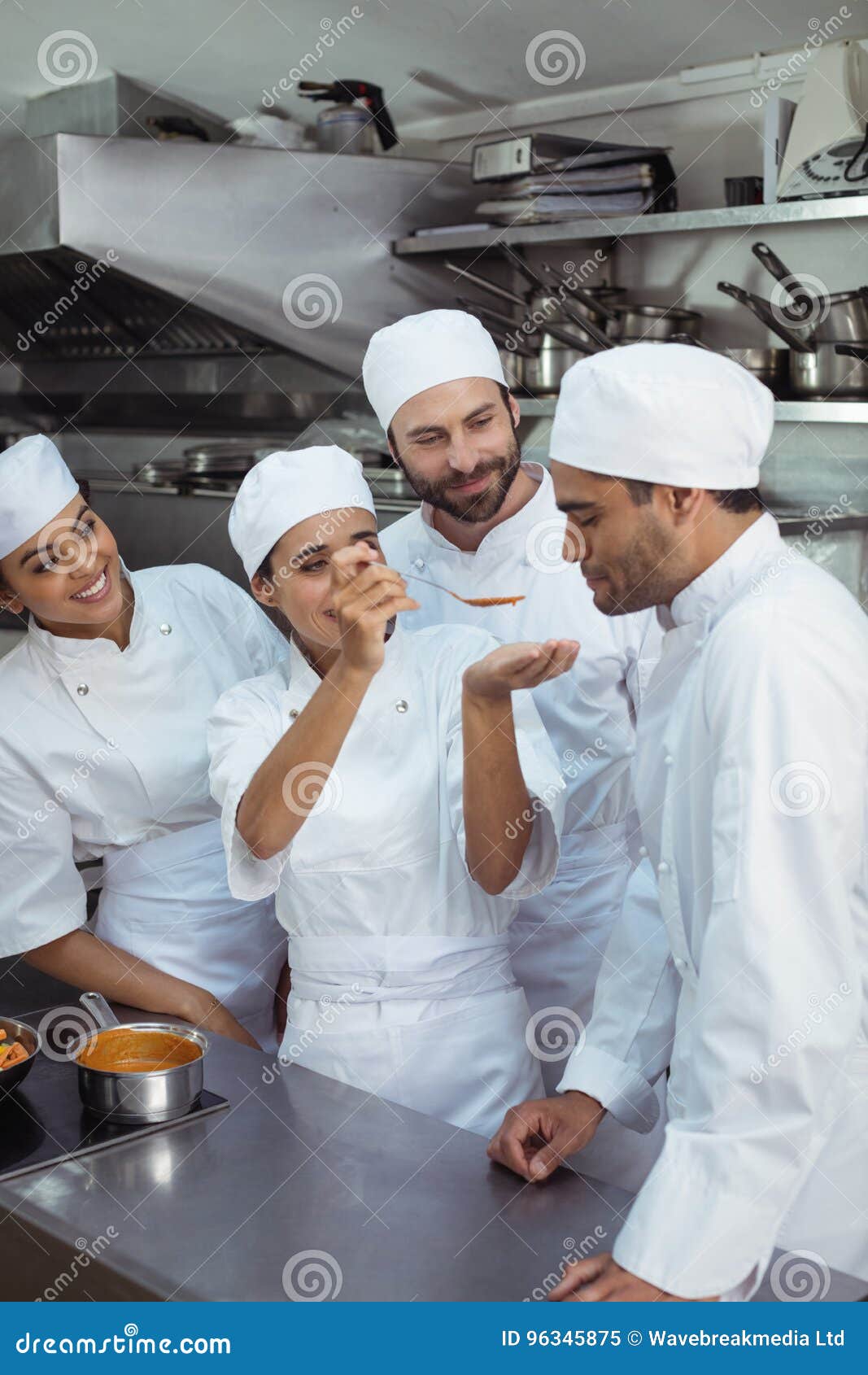 Chef Tasting Food To Colleague in Kitchen Stock Image - Image of ...