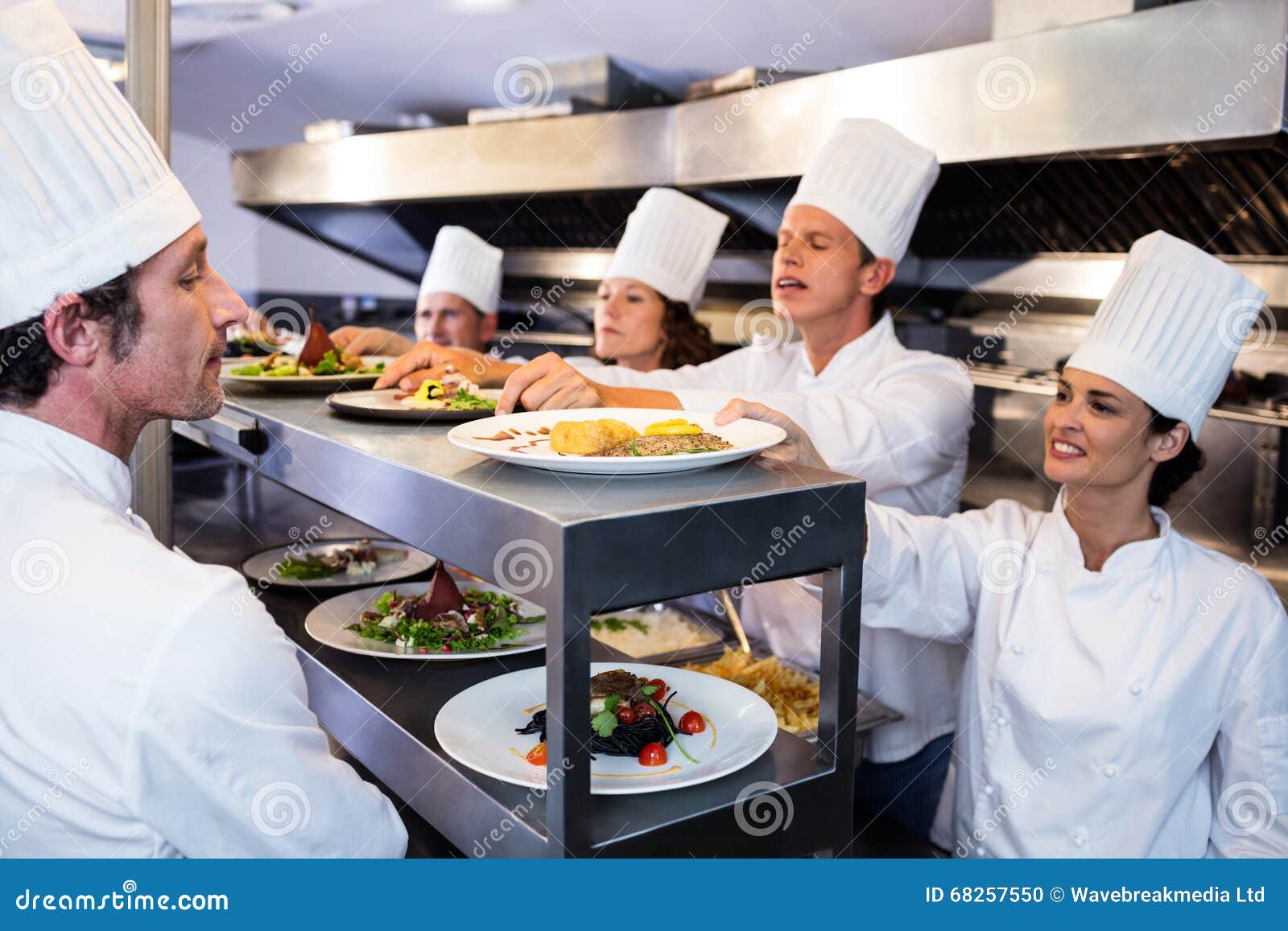 Chefs Handing Dinner Plates through Order Station Stock Photo - Image ...