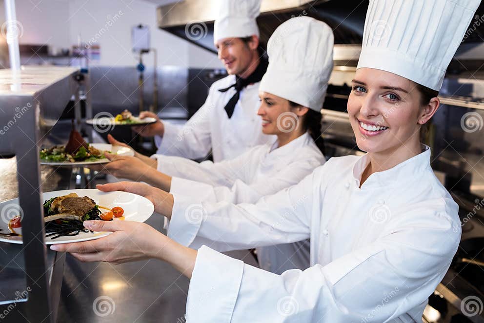 Chefs Handing Dinner Plates through Order Station Stock Photo - Image ...
