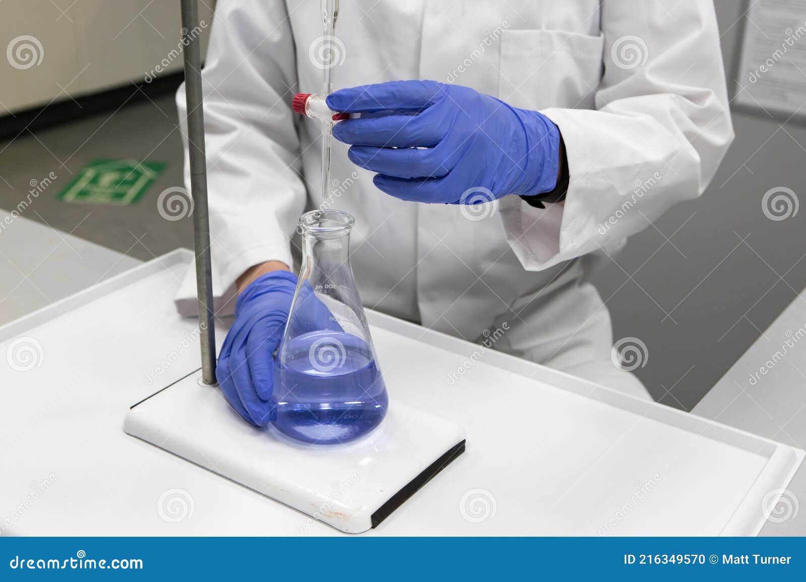 Chemist with Gloved Hands and a White Labcoat in a Laboratory Analysing ...