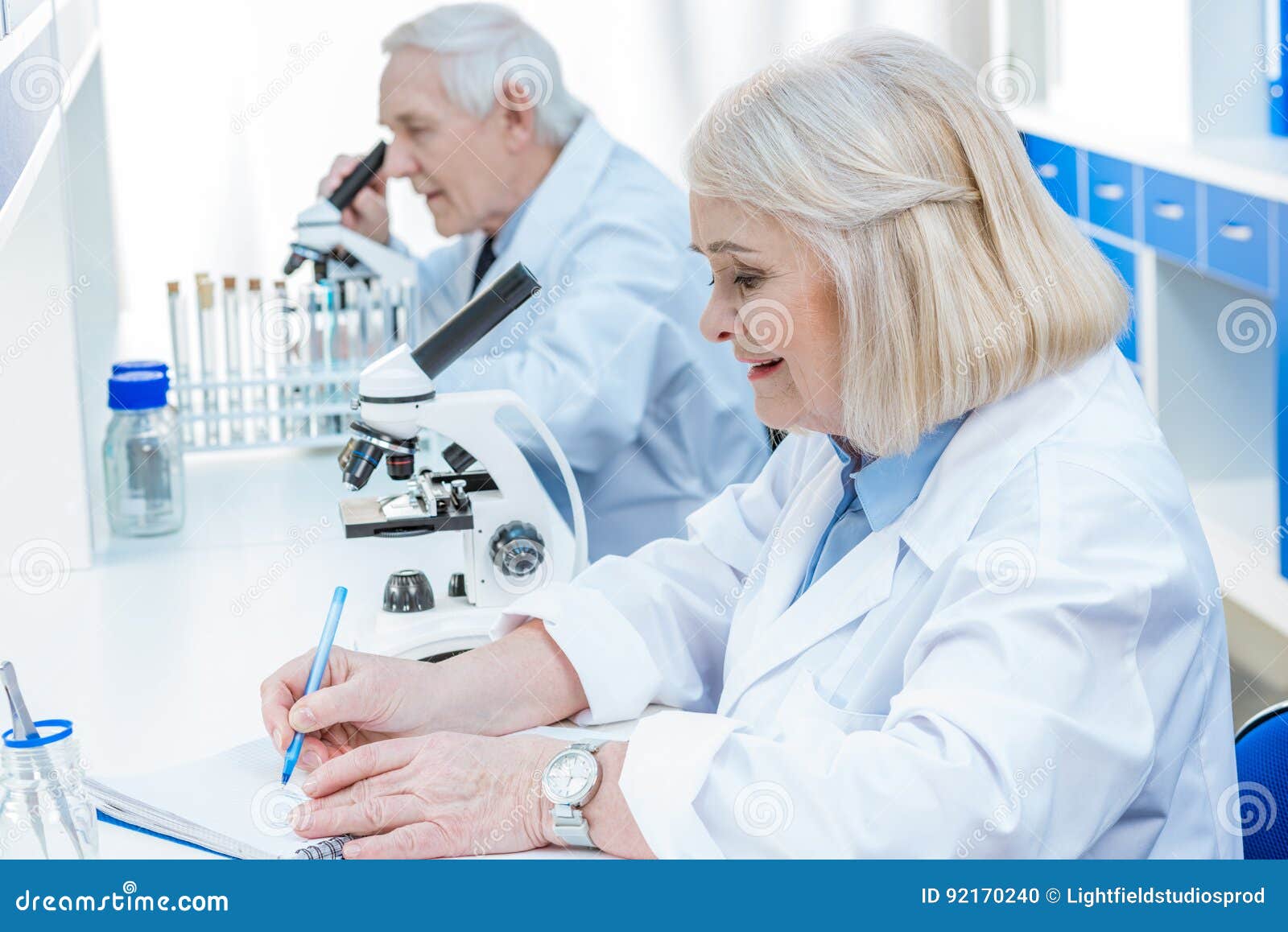 Chemists with Microscope Writing in Notepad in Laboratory Stock Photo ...