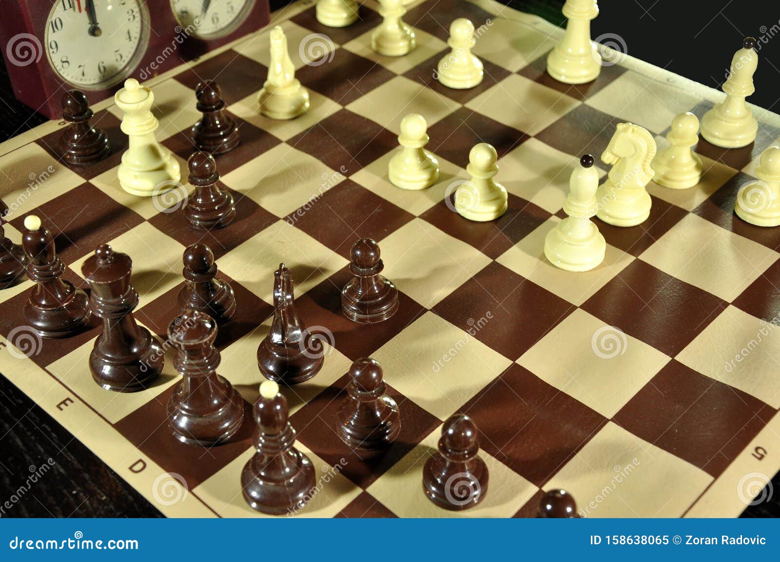 Chess Board with Black Figures in Focus and Clock in Black Background ...