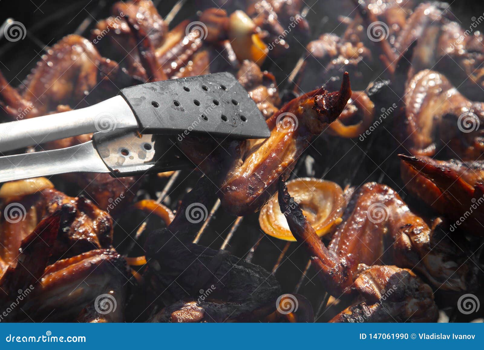 Chicken Wing Hold in Nippers, Smoked, on Barbecue Grill Stock Photo ...