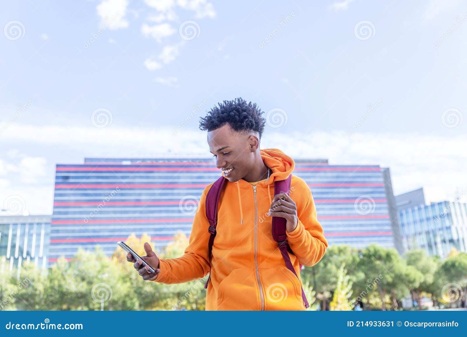 Chico Moreno De Amplia Sonrisa Mira Su Celular Imagen de archivo ...