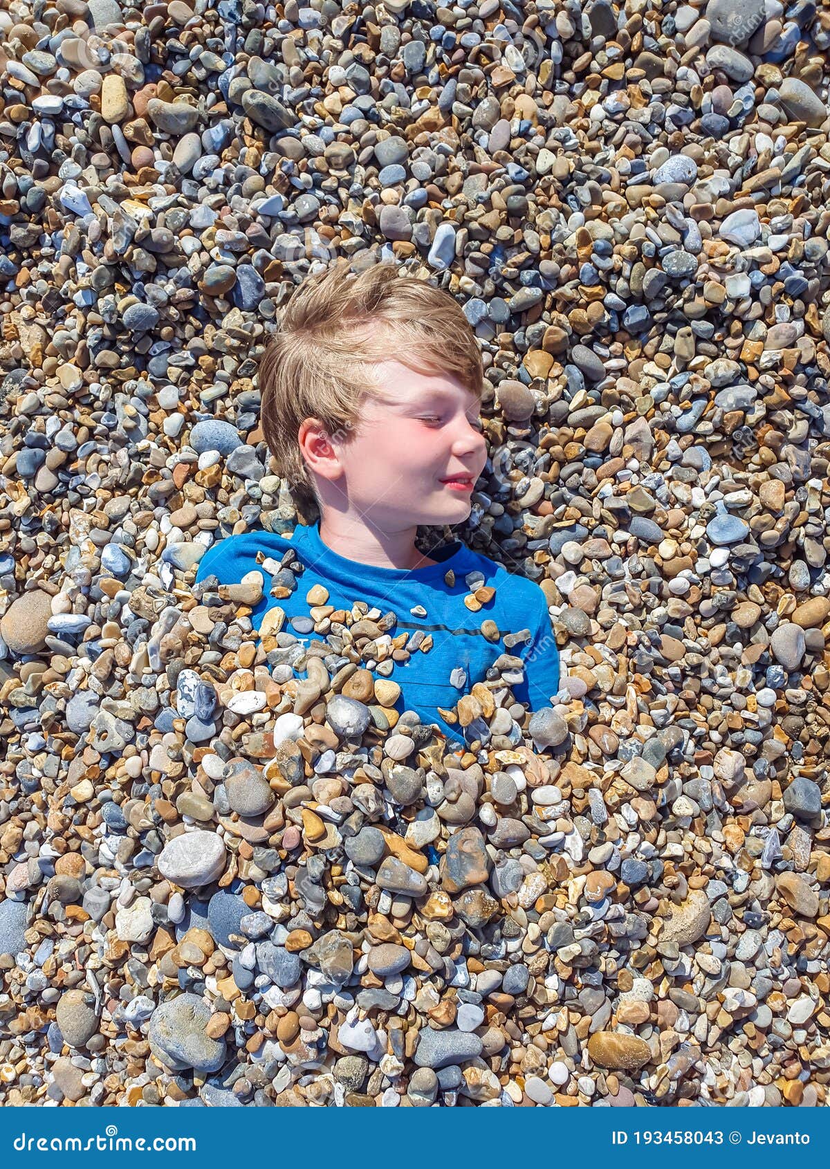 Child Boy Under Pebbles Stones on British Seaside Beach on Sunny Day ...