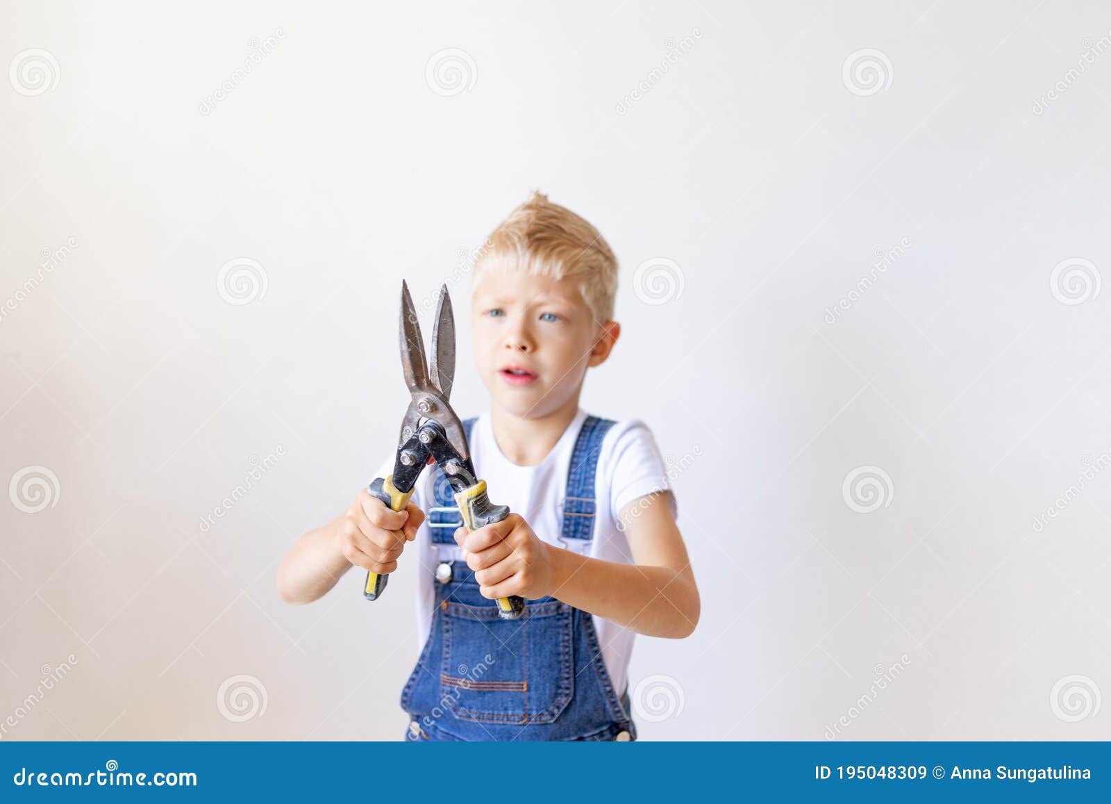 The Child is the Builder Holding a Pair of Tin Snips in Front of a ...