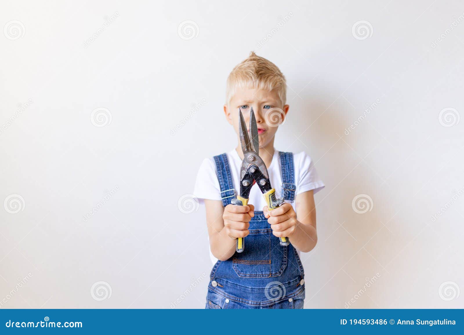 The Child is the Builder Holding a Pair of Tin Snips in Front of a ...