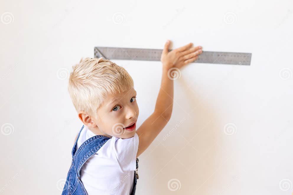 Child Builder Measures a White Wall with a Construction Ruler, Space ...