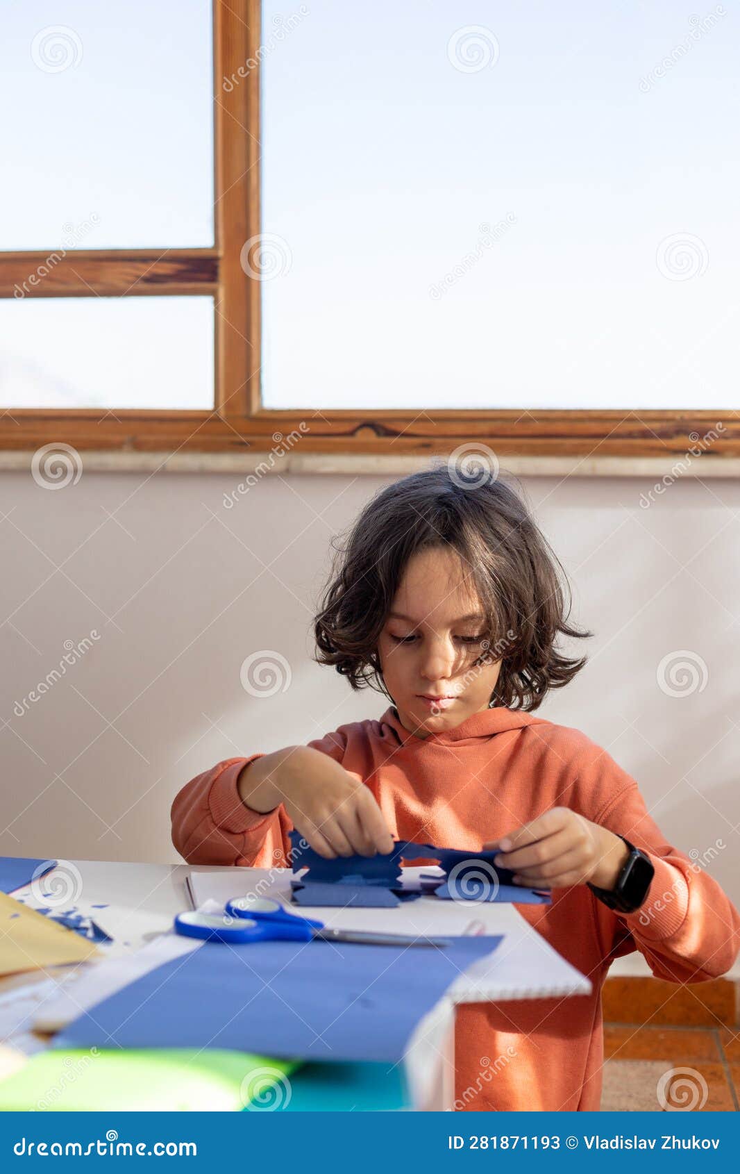 The Child Cuts Colored Paper with Scissors at the Table. the Boy Cuts a ...