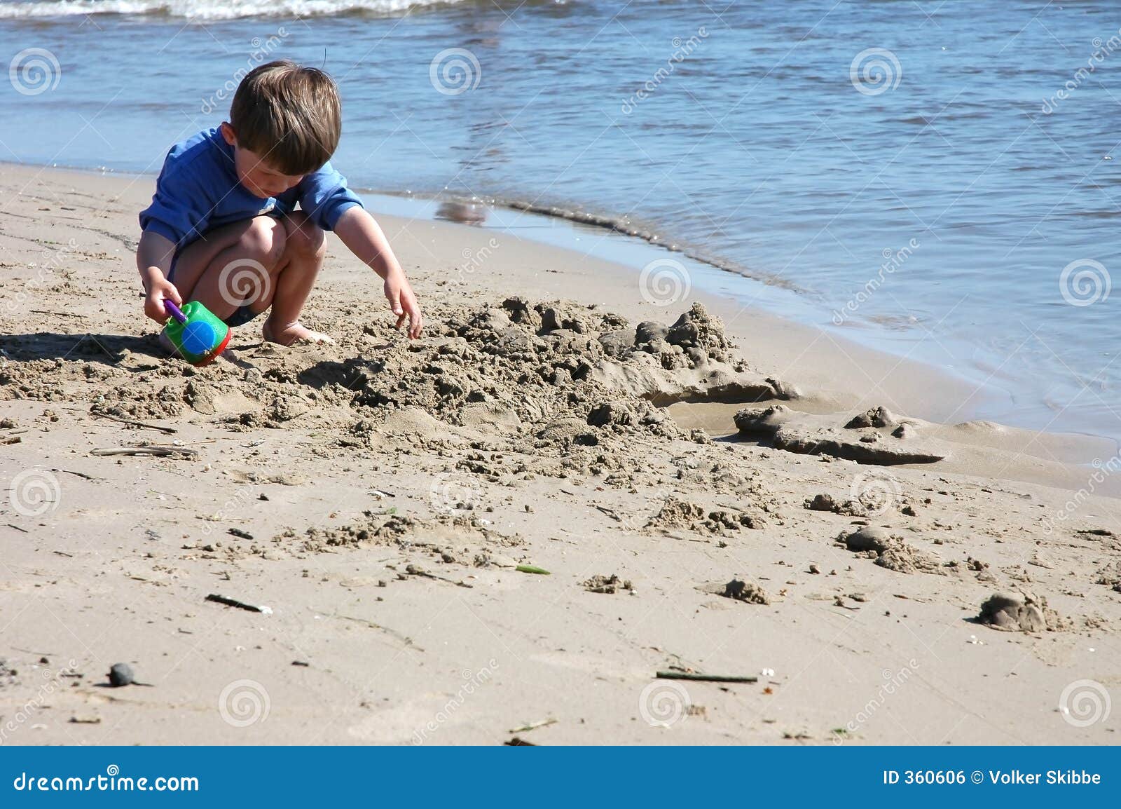 Child digging at the beach stock photo. Image of watering - 360606