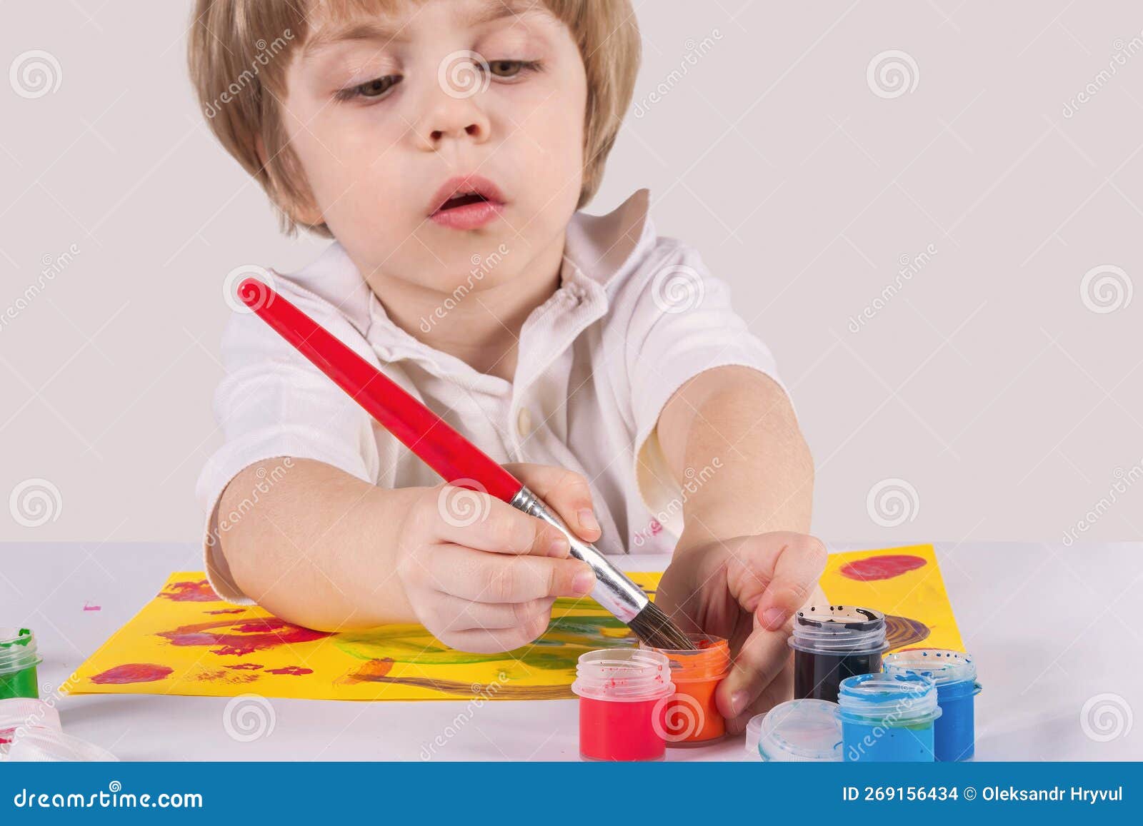 A Child Dips a Brush in Orange Paint To Draw Stock Photo - Image of ...