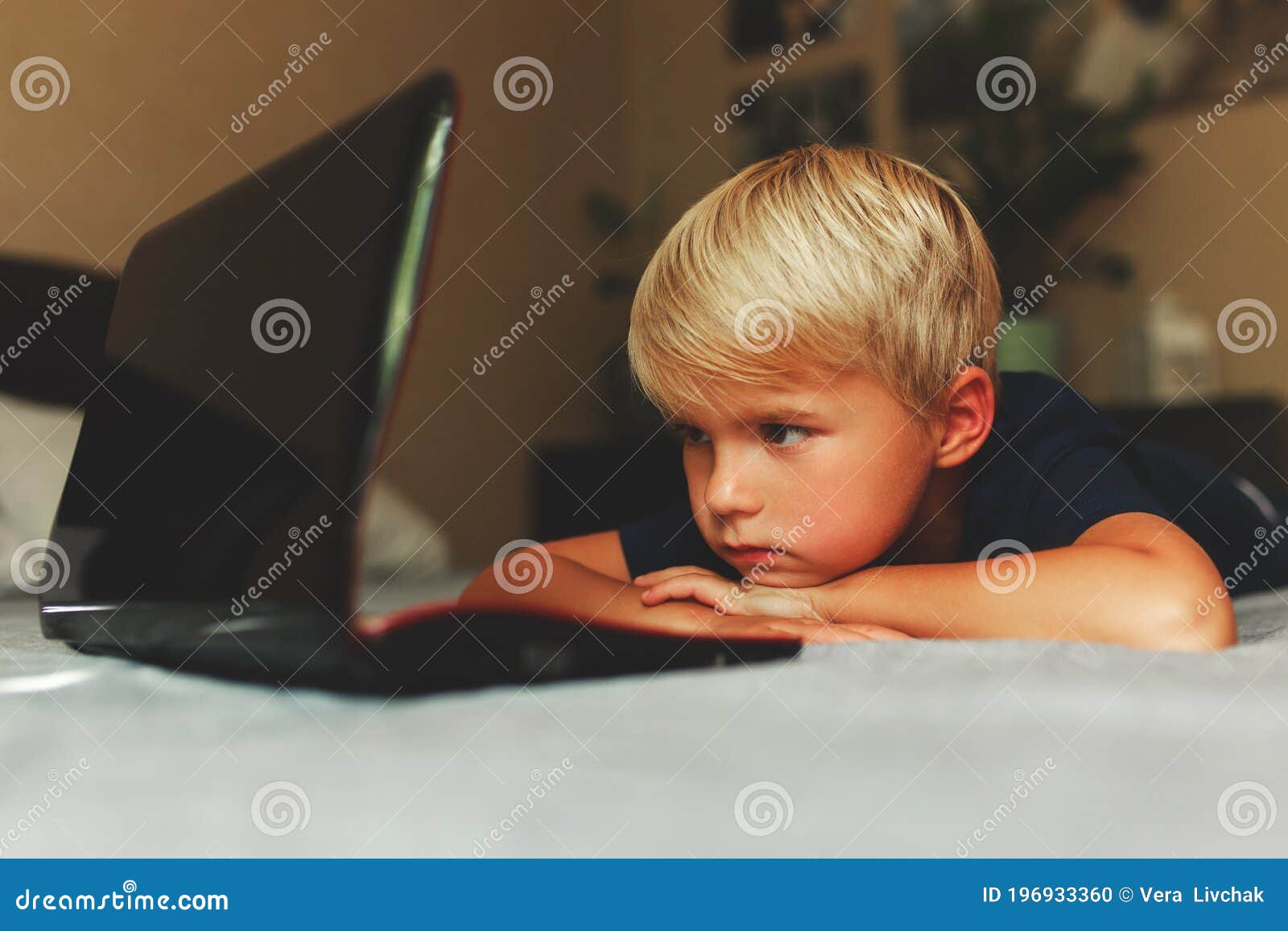 Child Does Homework , Lying in Bed Using His Laptop or Skyping. Stock ...