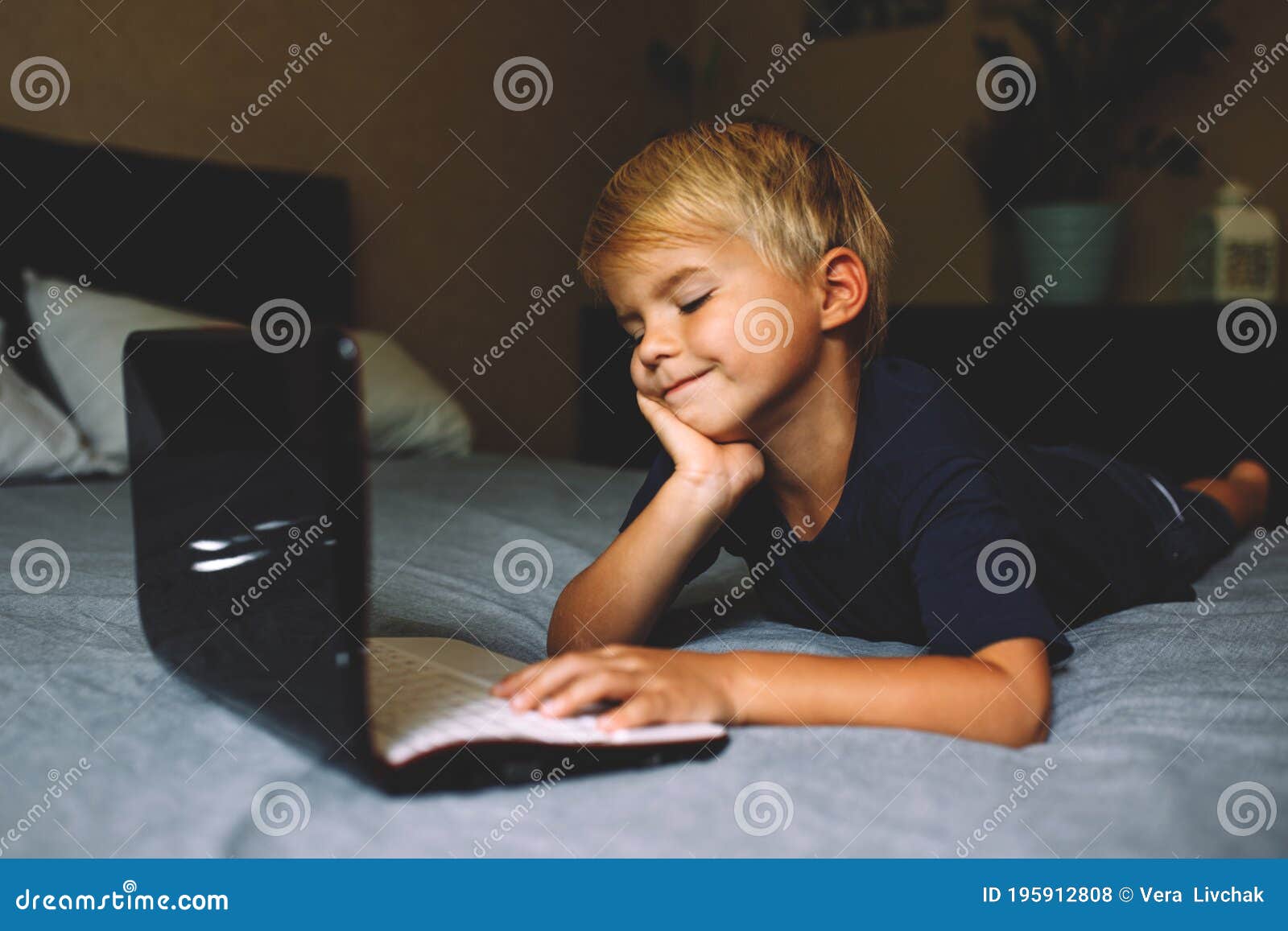Child Does Homework , Lying in Bed Using His Laptop or Skyping. Stock ...