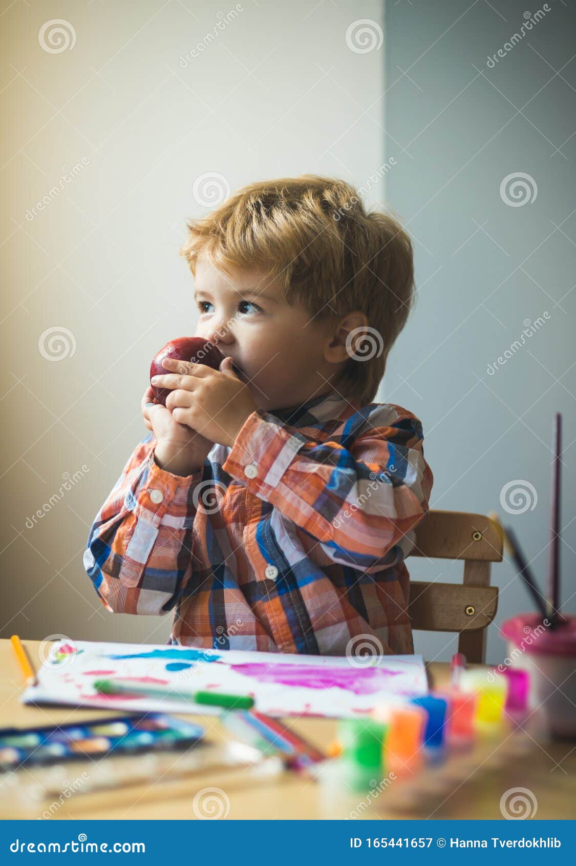 Child Eats Apple during Break at Draw Lesson. Healthy Snack for Child ...