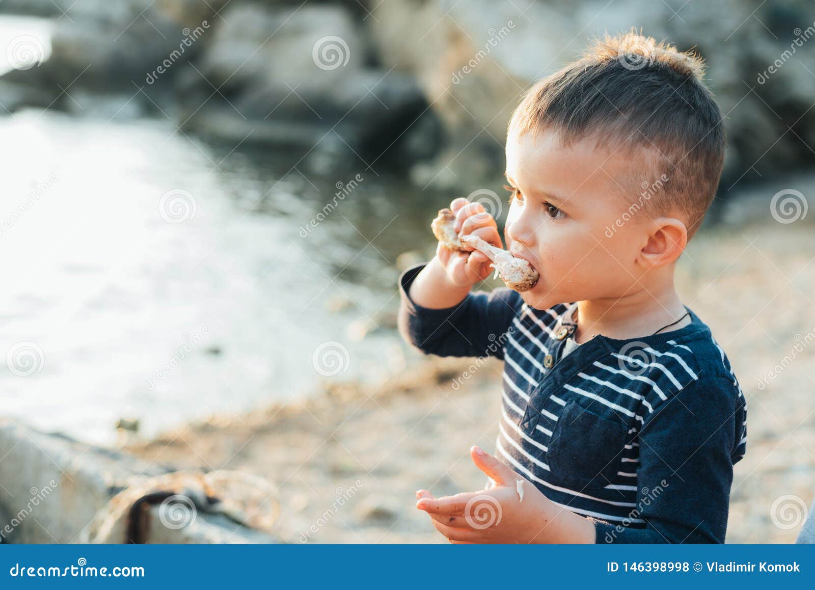 The Child Eats a Chicken Drumstick Cooked on the BBQ Stock Photo ...