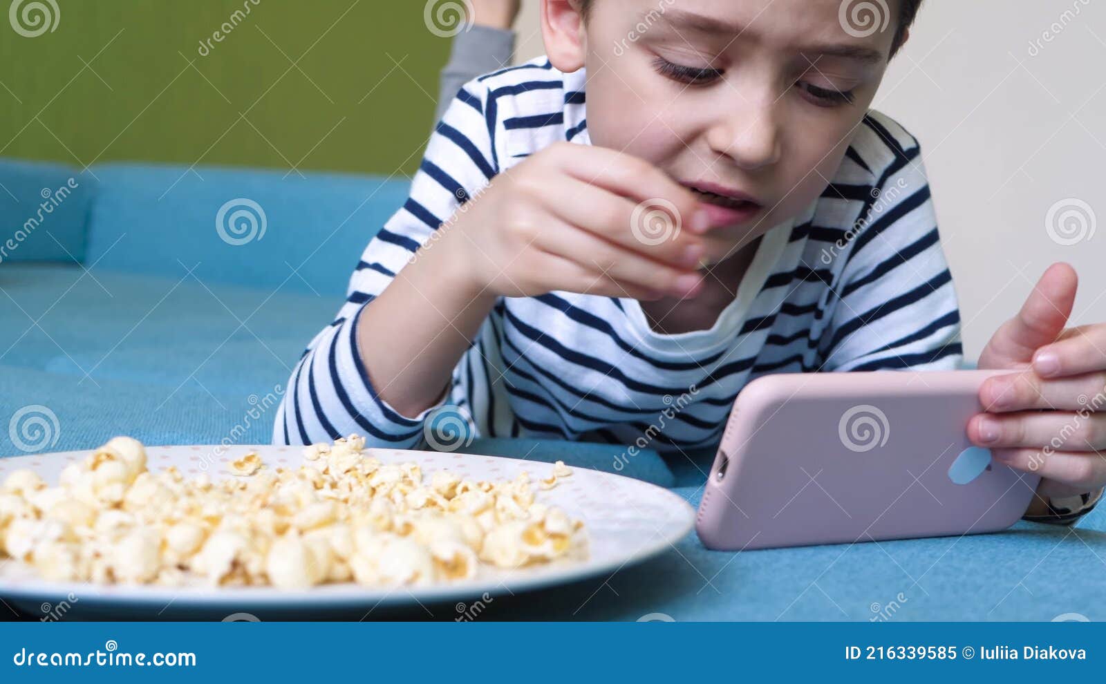 The Child Eats Popcorn, Lying on the Sofa in the Room and Spending Time ...