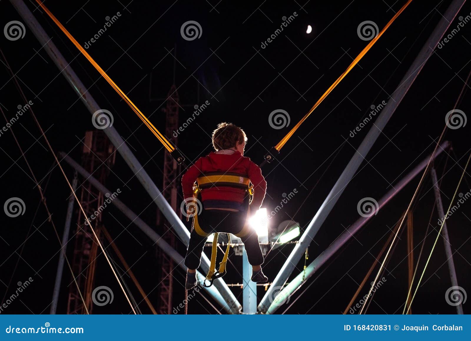 Child at a Fair Jumping on a Bungee Trampoline during the Night Stock ...