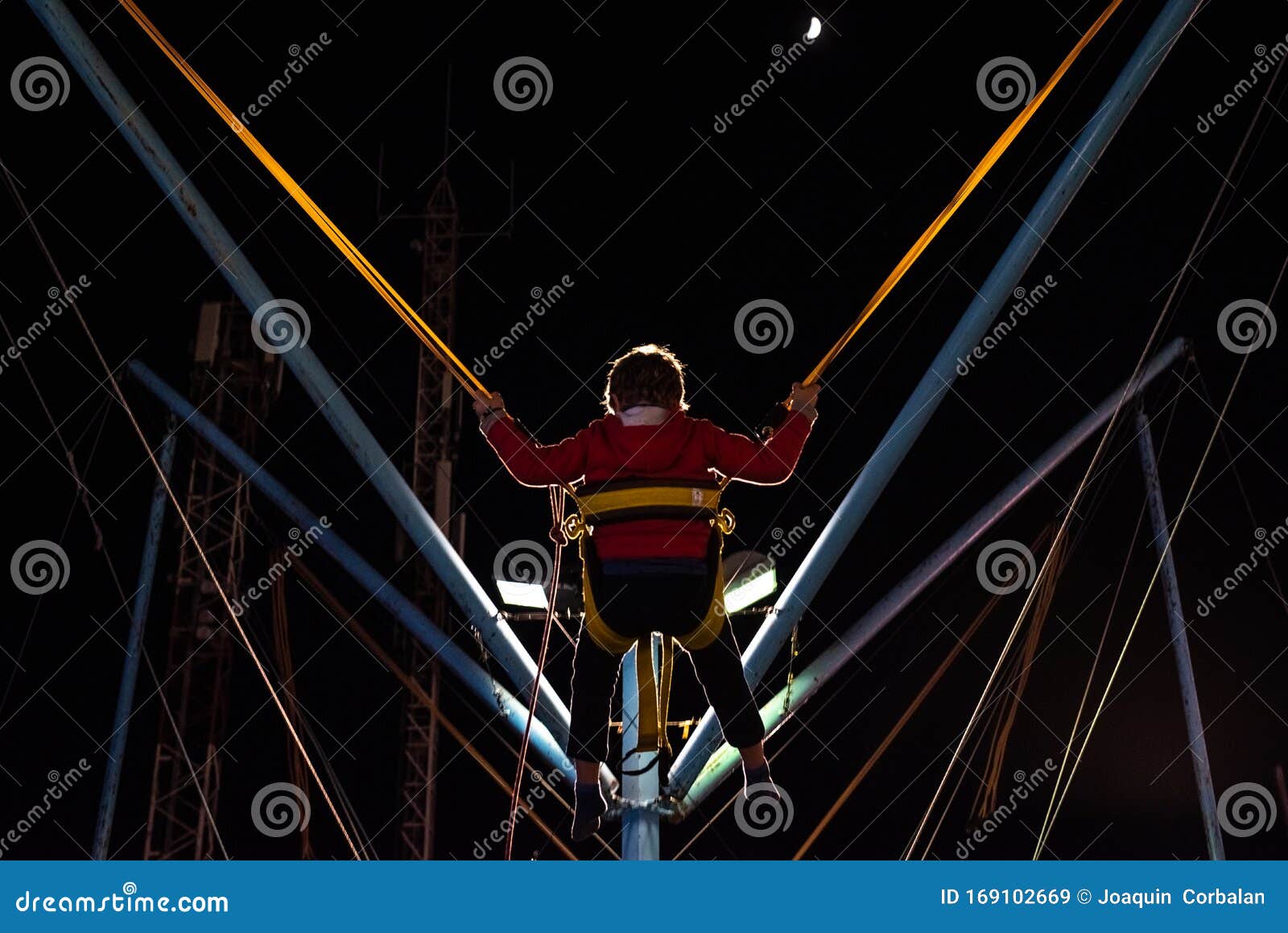 Child at a Fair Jumping on a Bungee Trampoline during the Night Stock ...